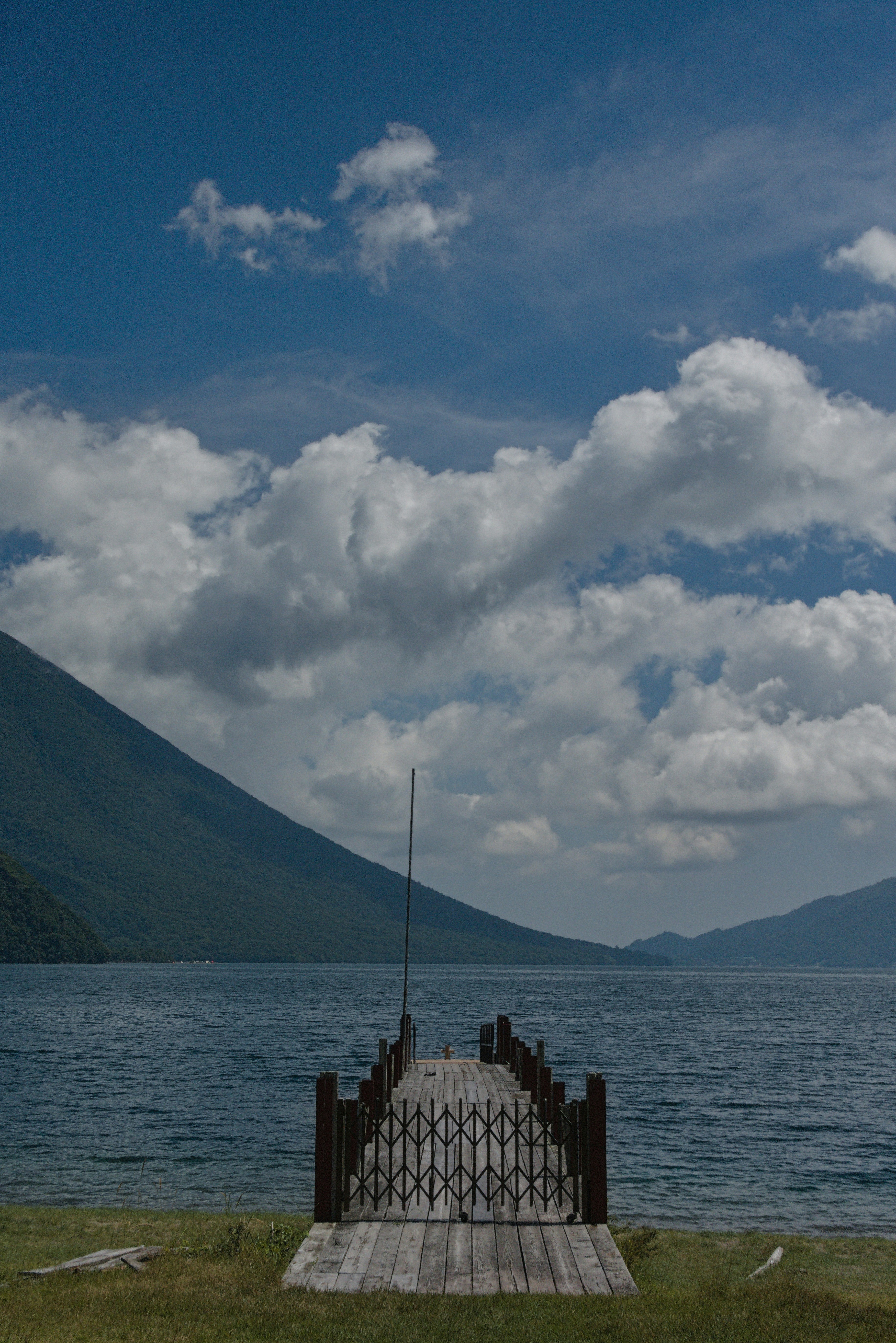 Dock in Senjugahama, over Chuzenji lake | Wooden pier on a calm lake with mountains and clouds