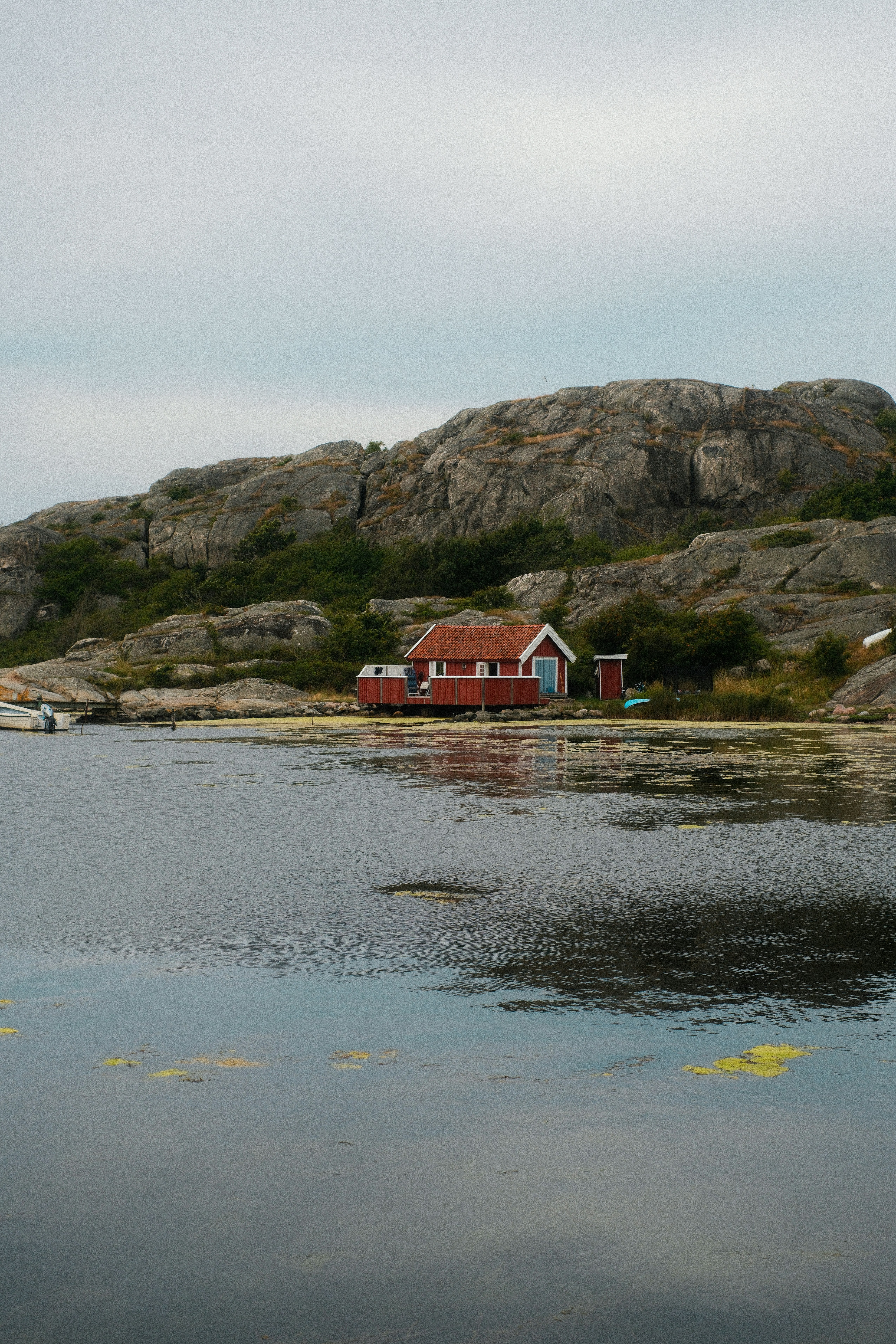 Red Swedish summer house on the Island of Styrsö in the Gothenburg Archipelago | Red house on rocky shore with calm water