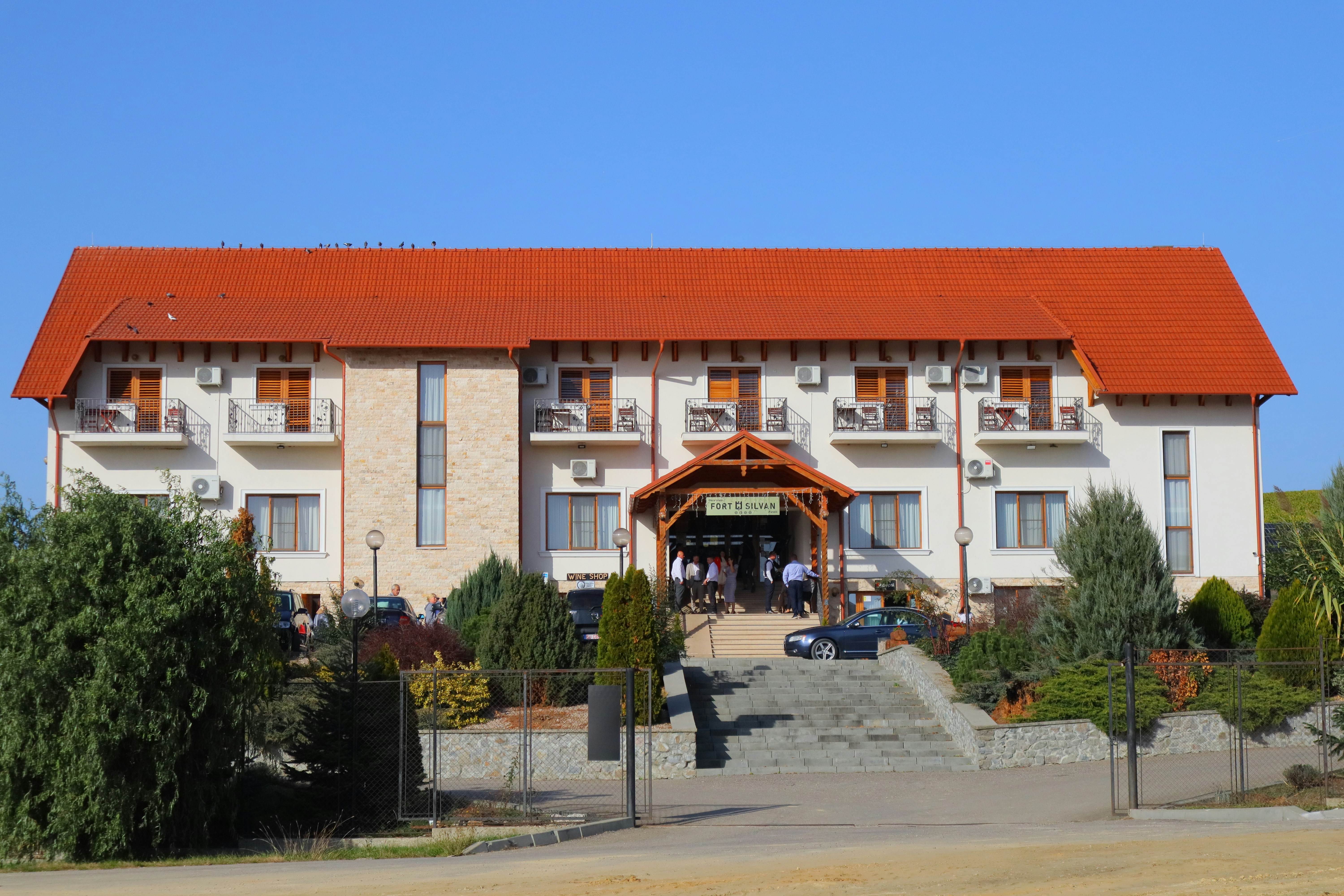 Camăr 2024, Romania | Large hotel building with red roof and green trees