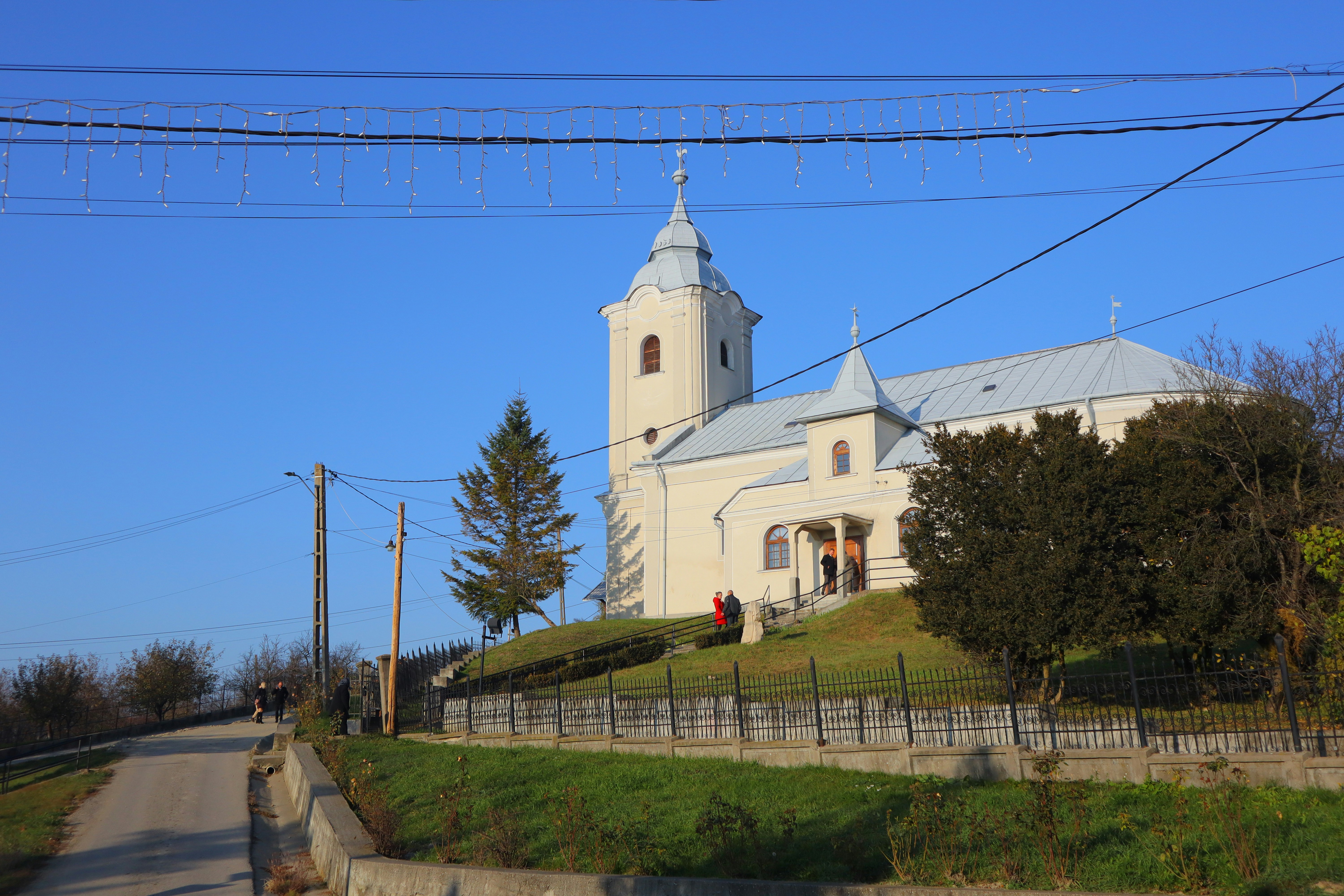 Șărmășag 2024, Romania | White church on a grassy hill under a blue sky.