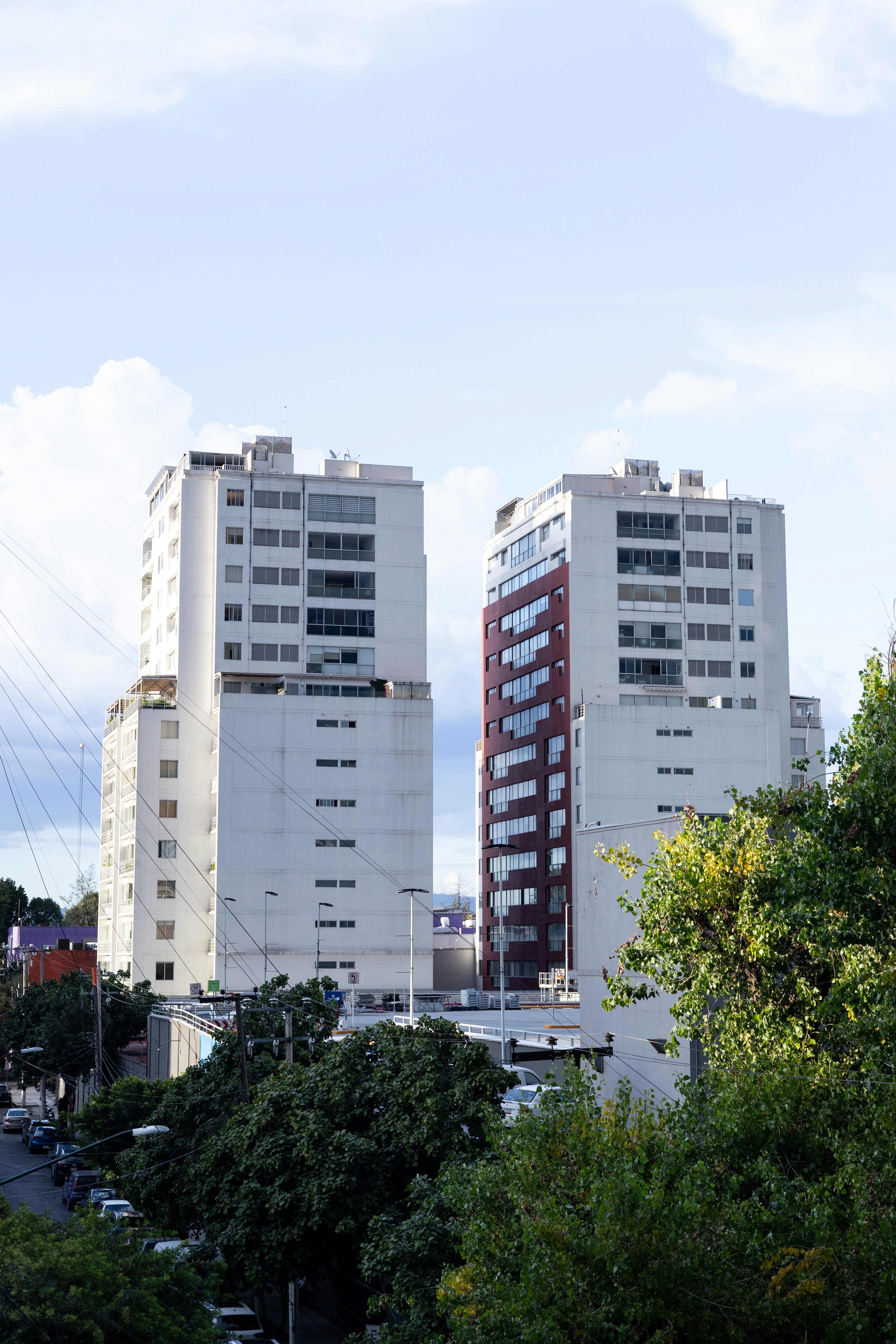 Two tall apartment buildings with trees in foreground.