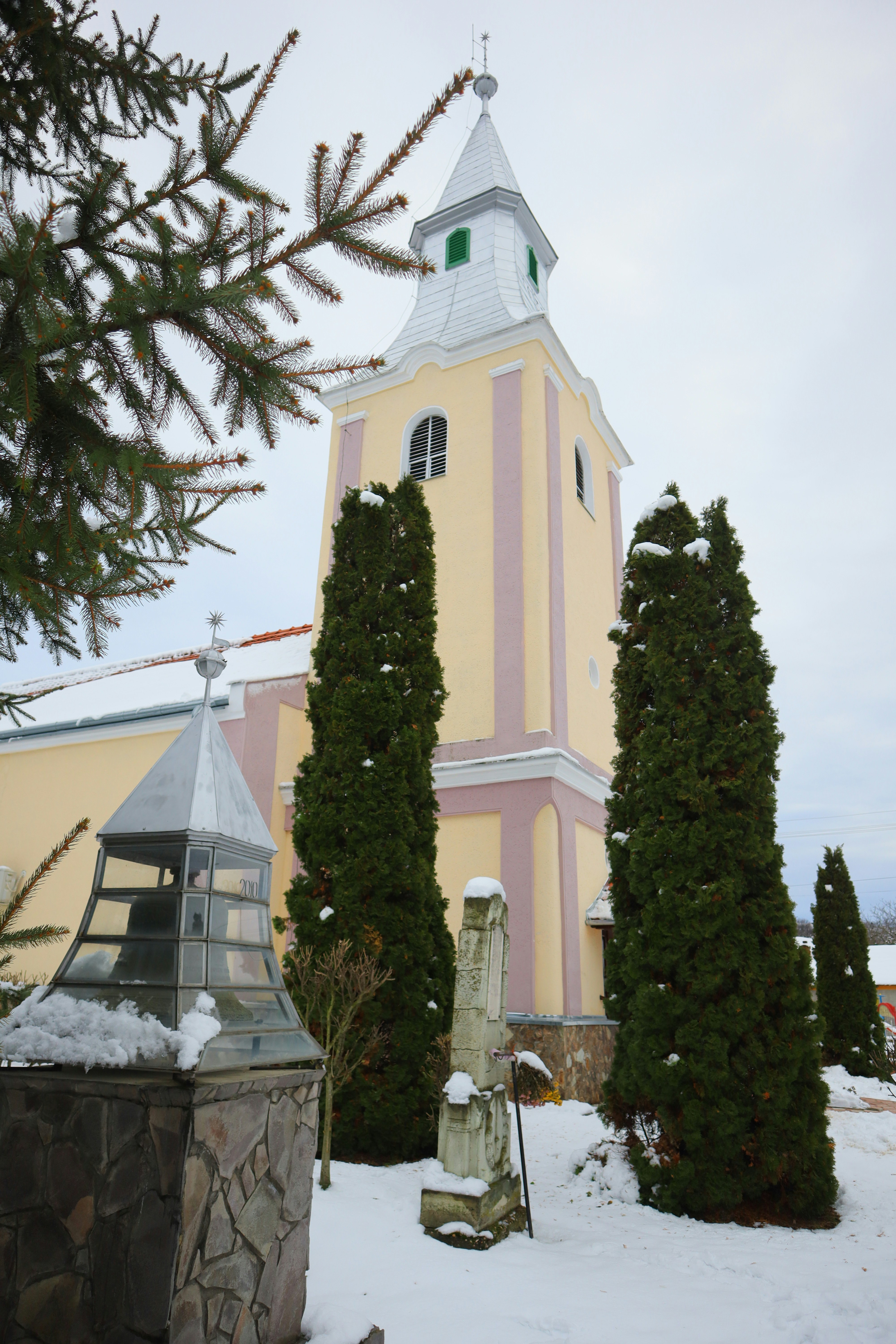 Leşmir 2024, Romania | A church tower with cypress trees in snow.