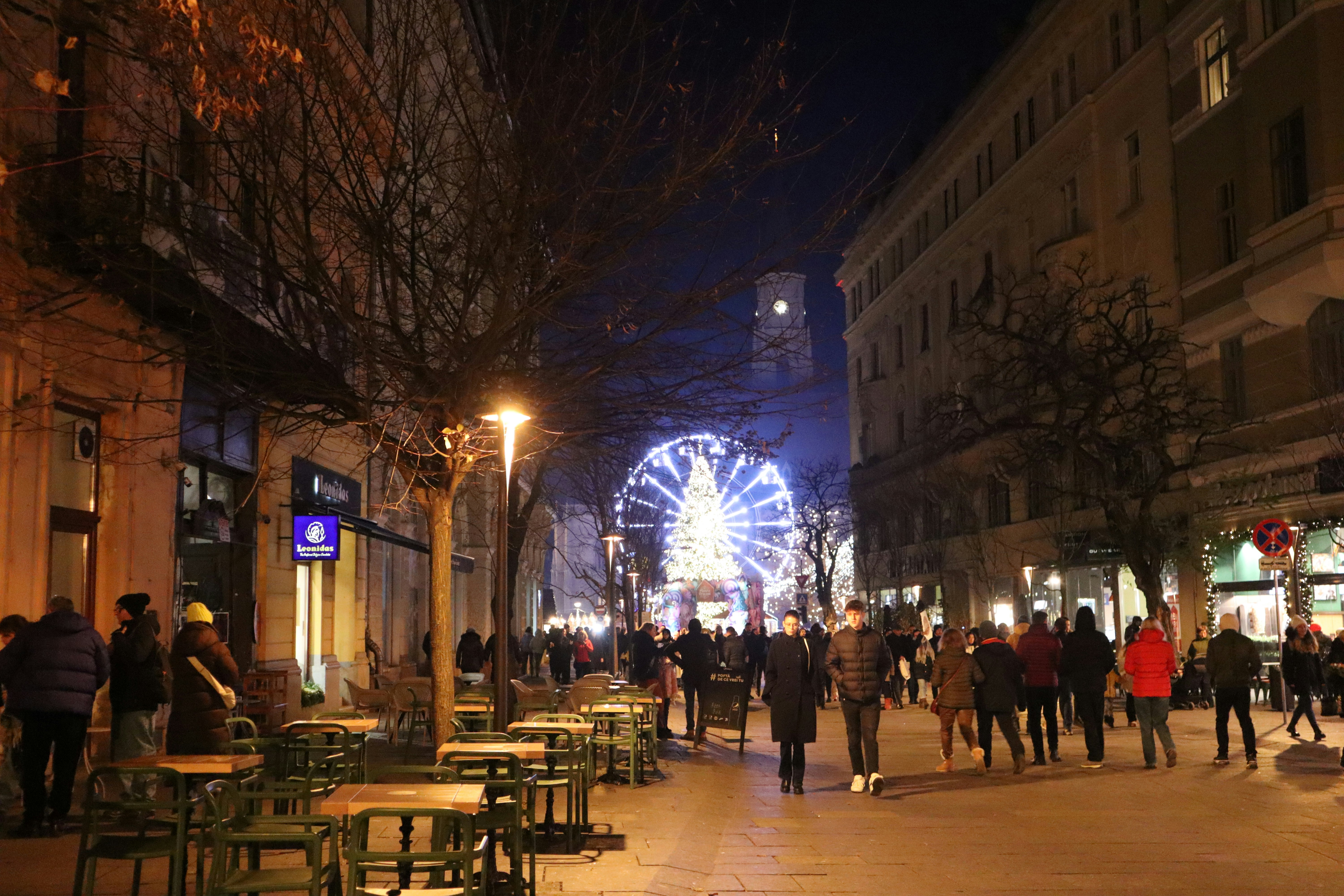 Cluj - Napoca 2024, Romania | People walking on a street with a ferris wheel at night.