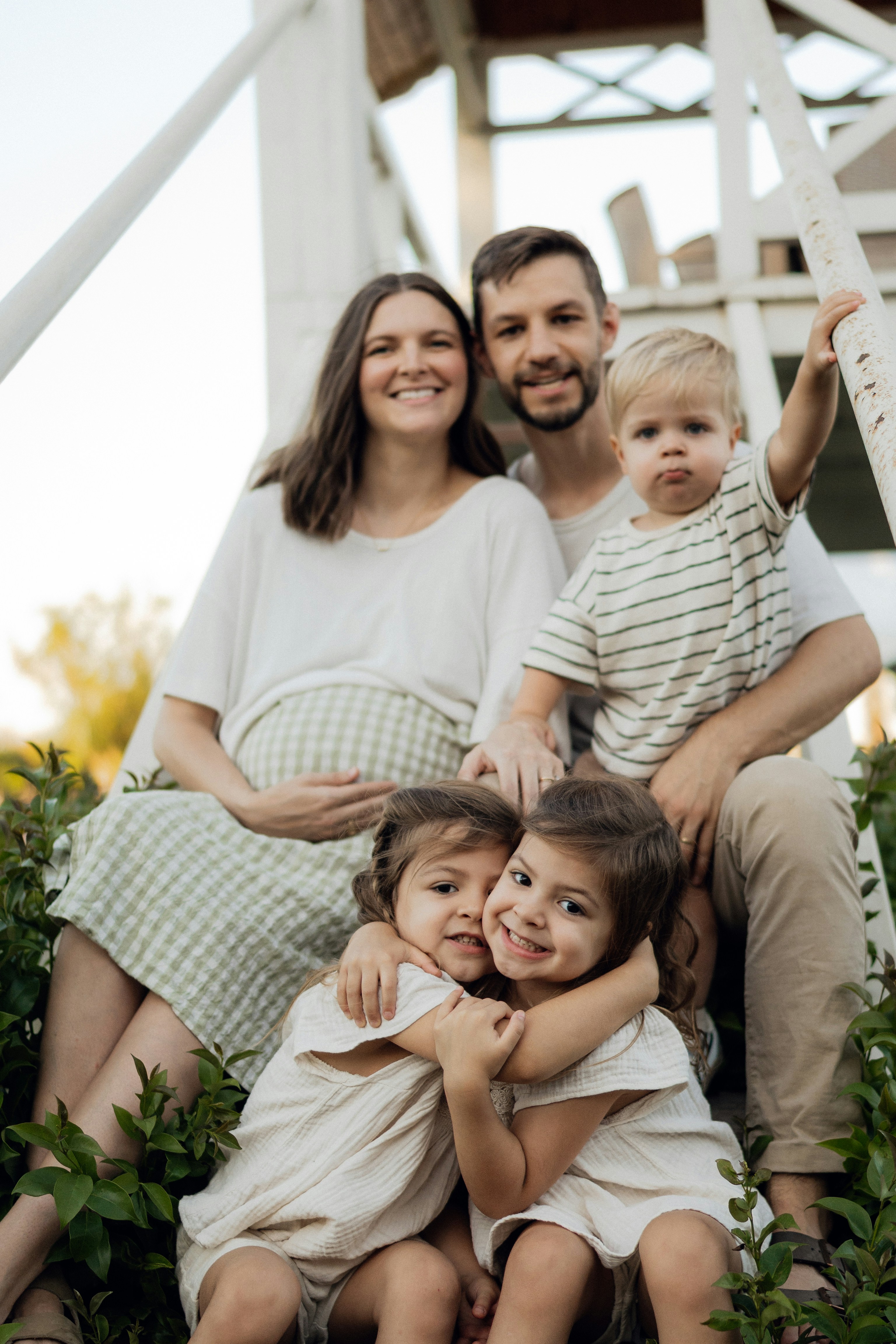 Pregnant mother and father with three children sitting on steps. photo ...