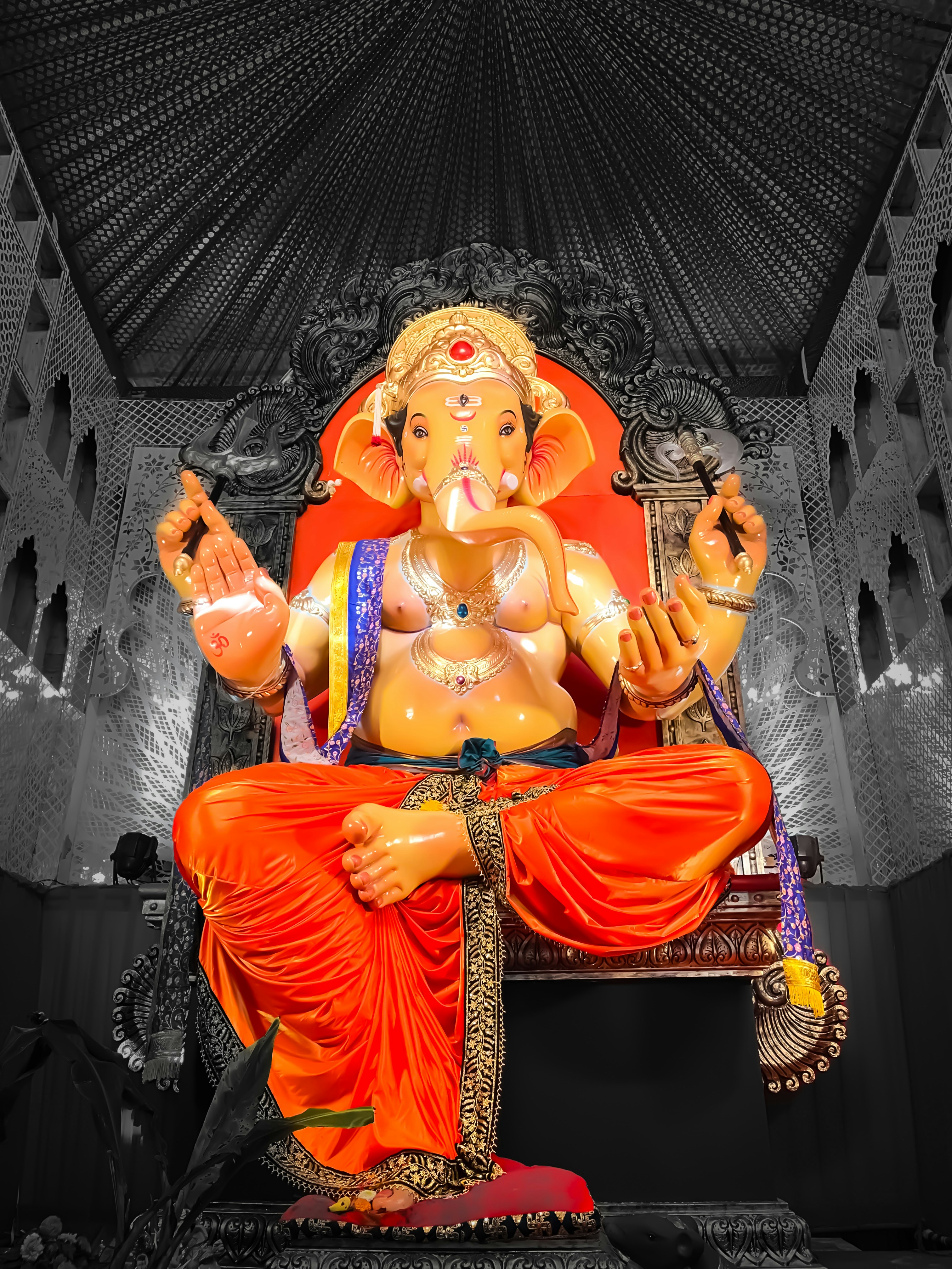 Crimson Deity on a Velvet Throne: Ganesha in Orange Amid a Monochrome Shrine