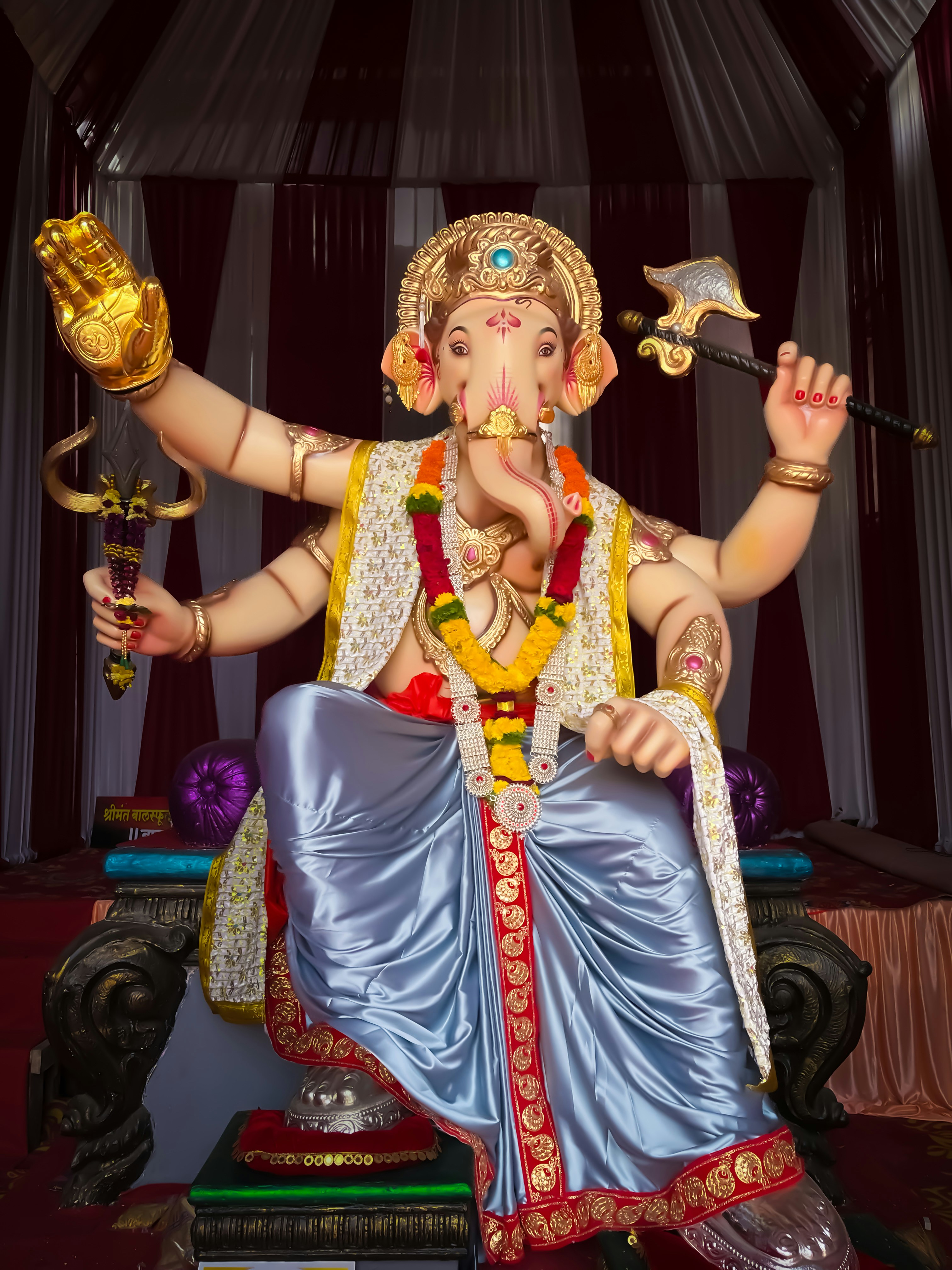 Crowned Protector: Ganesha in ceremonial splendor beneath velvet drapes