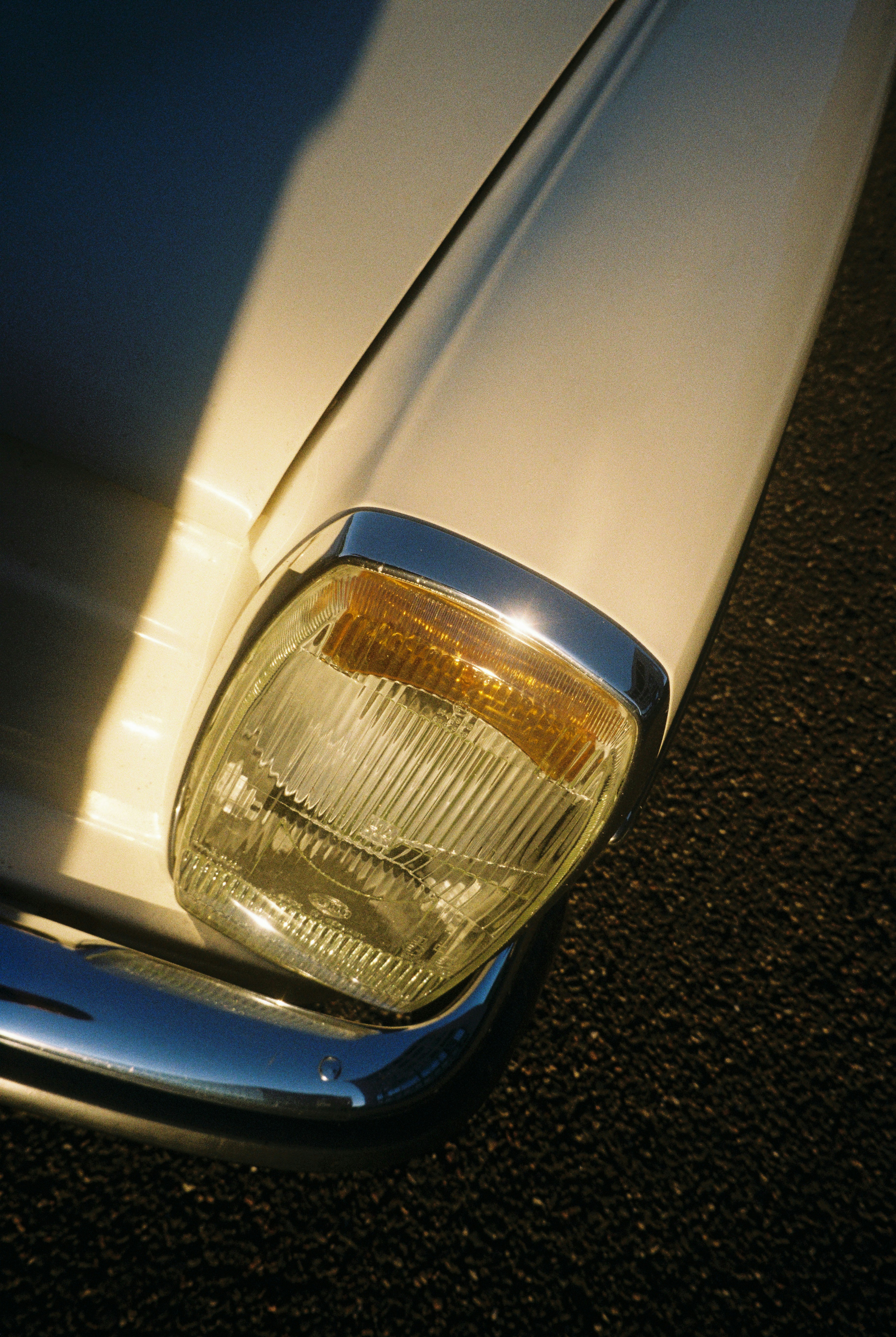Shot on Kodak Gold 200 | Close-up of a vintage car headlight with chrome accents.