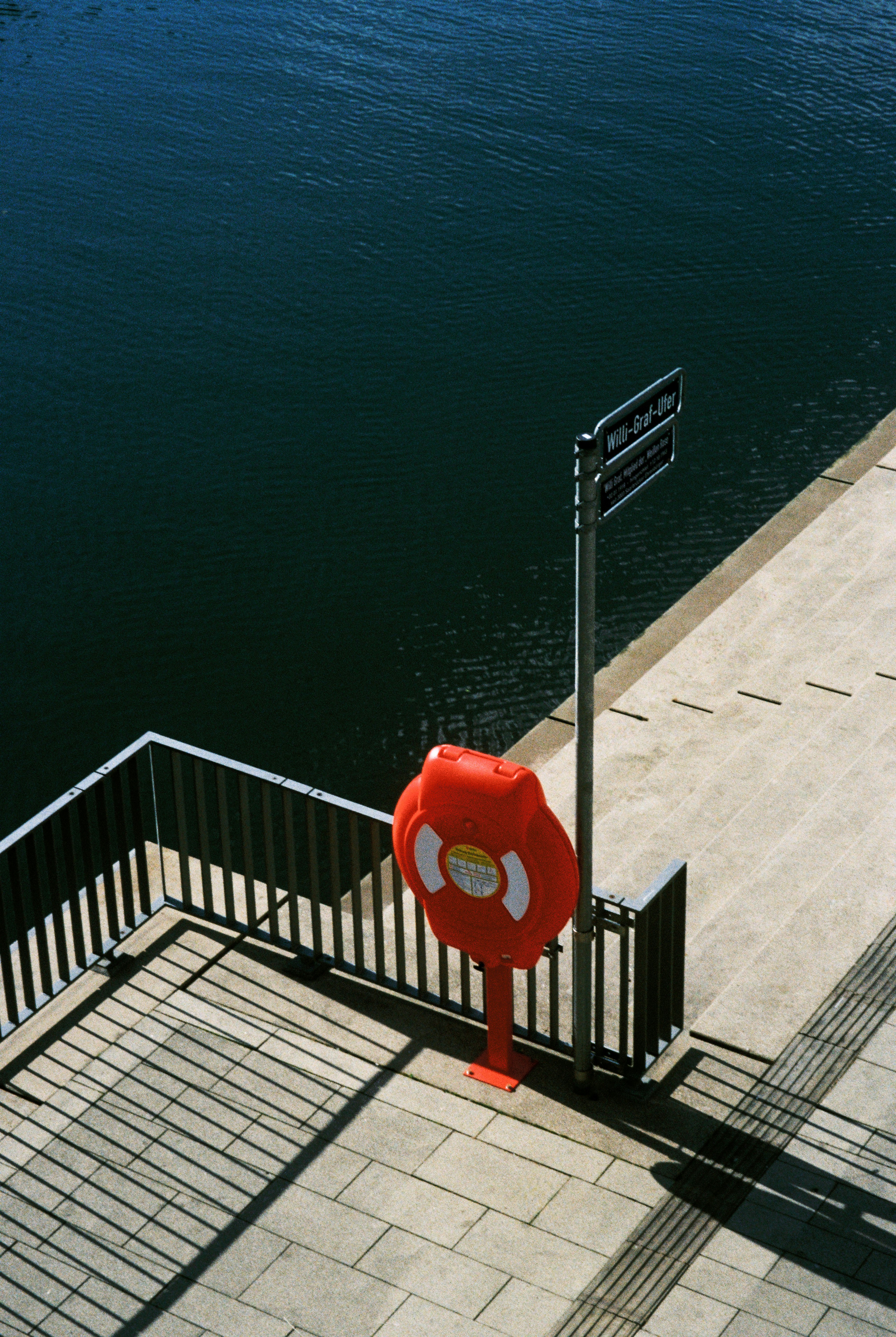 Shot on Kodak Gold 200 | Orange life preserver by a waterfront railing