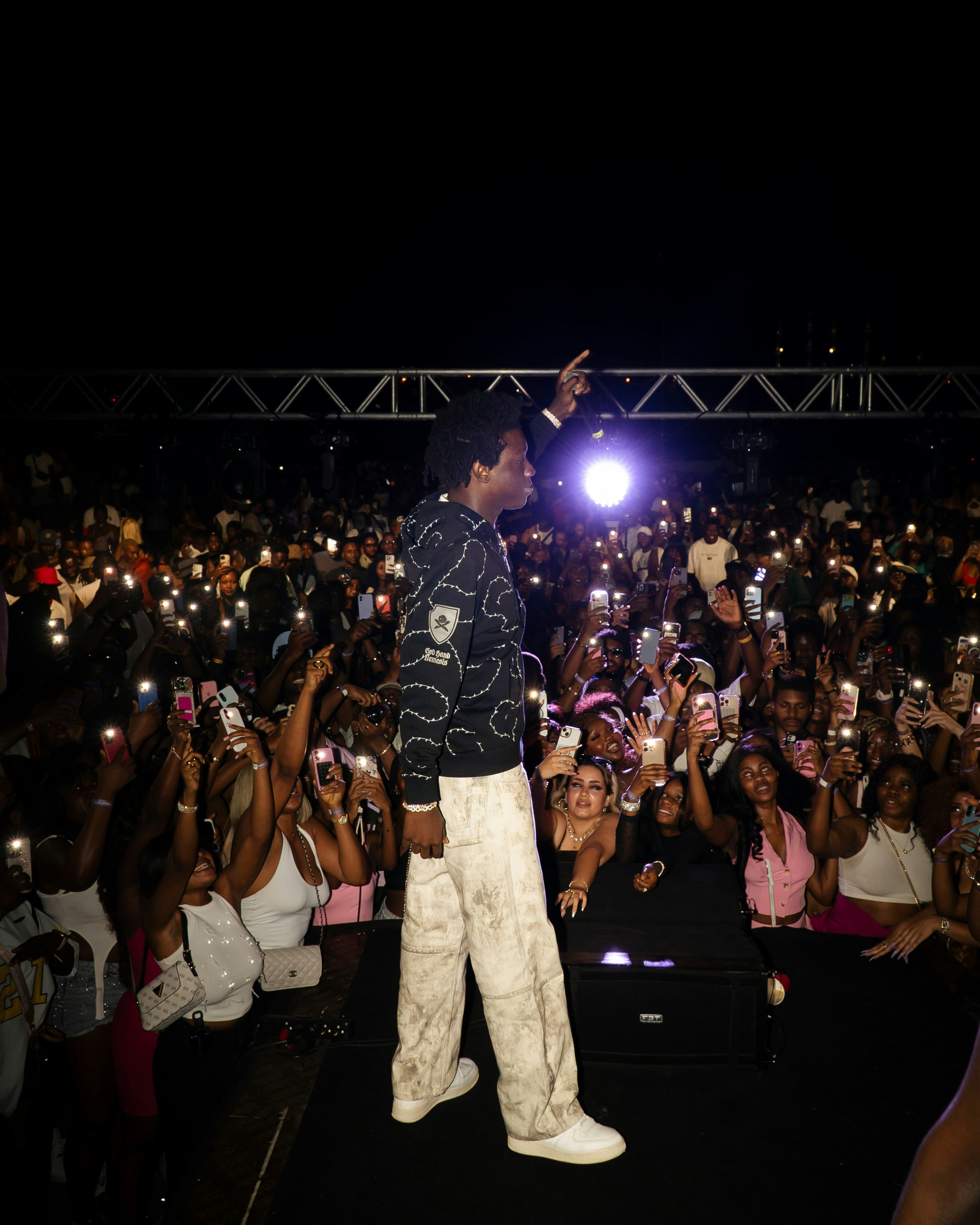 Performer on stage with a crowd holding up phones.