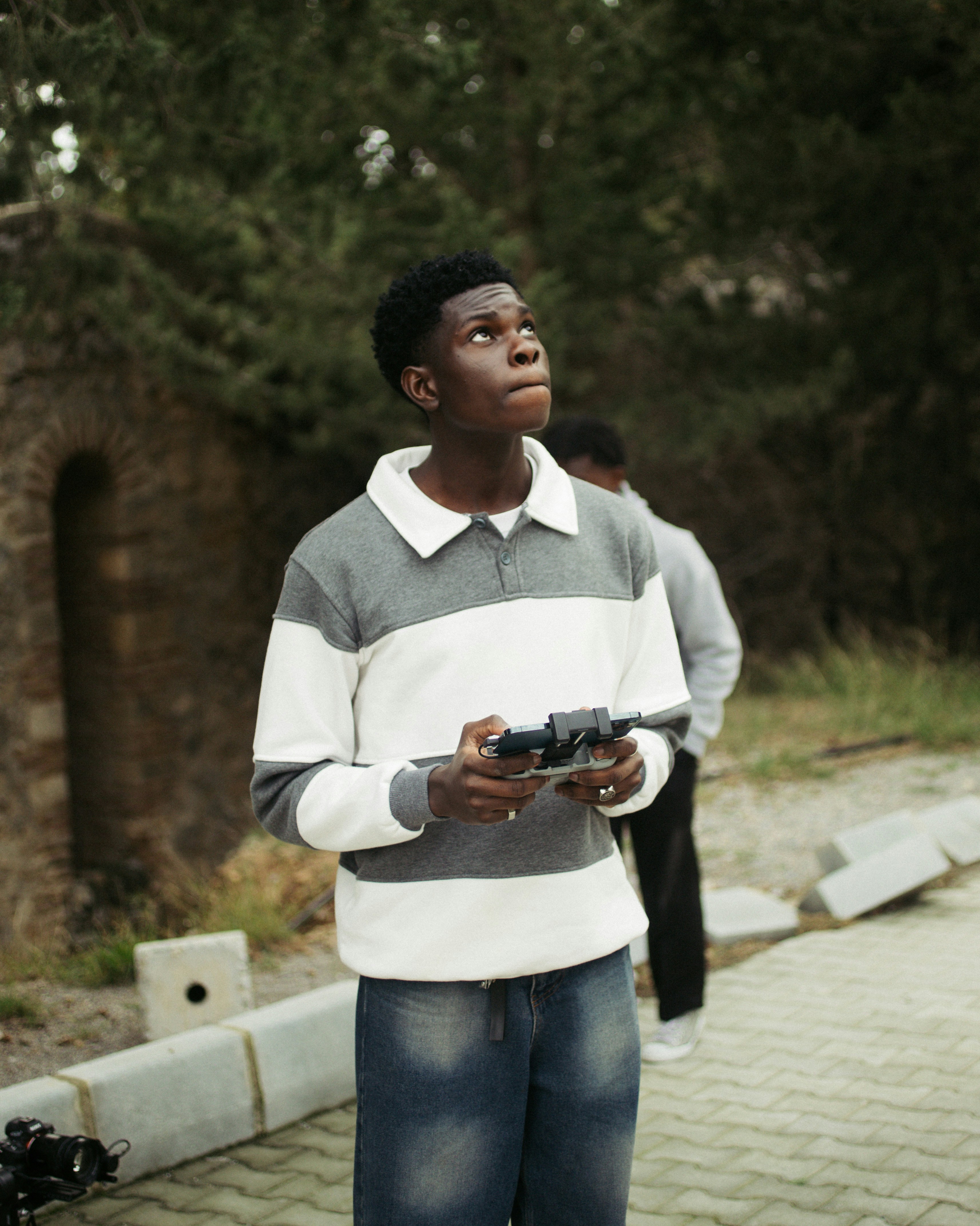 Gazing Skyward: a teen with a drone controller in a quiet courtyard