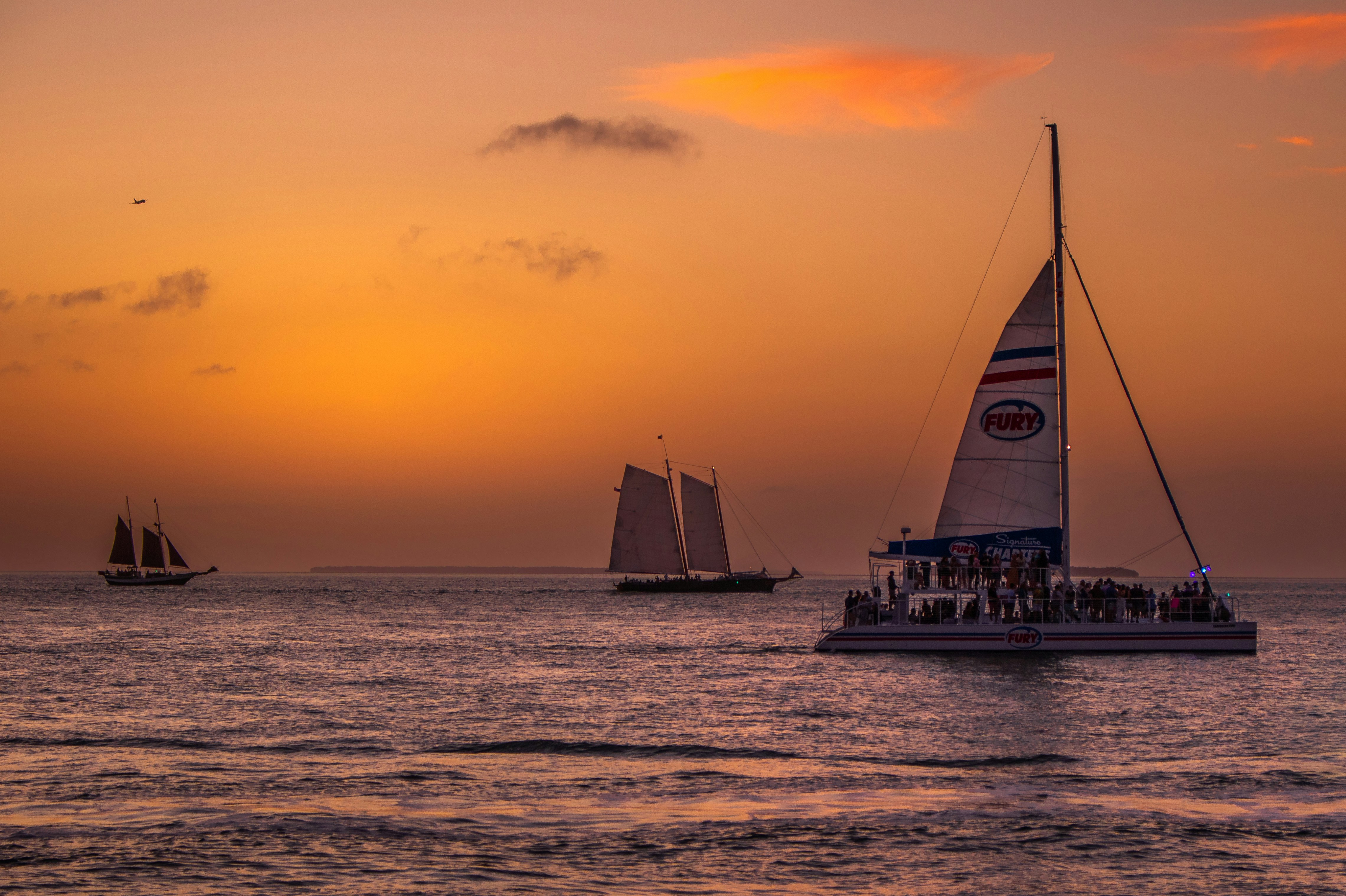 A dramatic sunset of the Atlantic Ocean photographed from Fort Zachary Taylor Historic State Park Beach in Key West, Florida - the southern eastern most point of continental USA. | Sailboats on the ocean at sunset