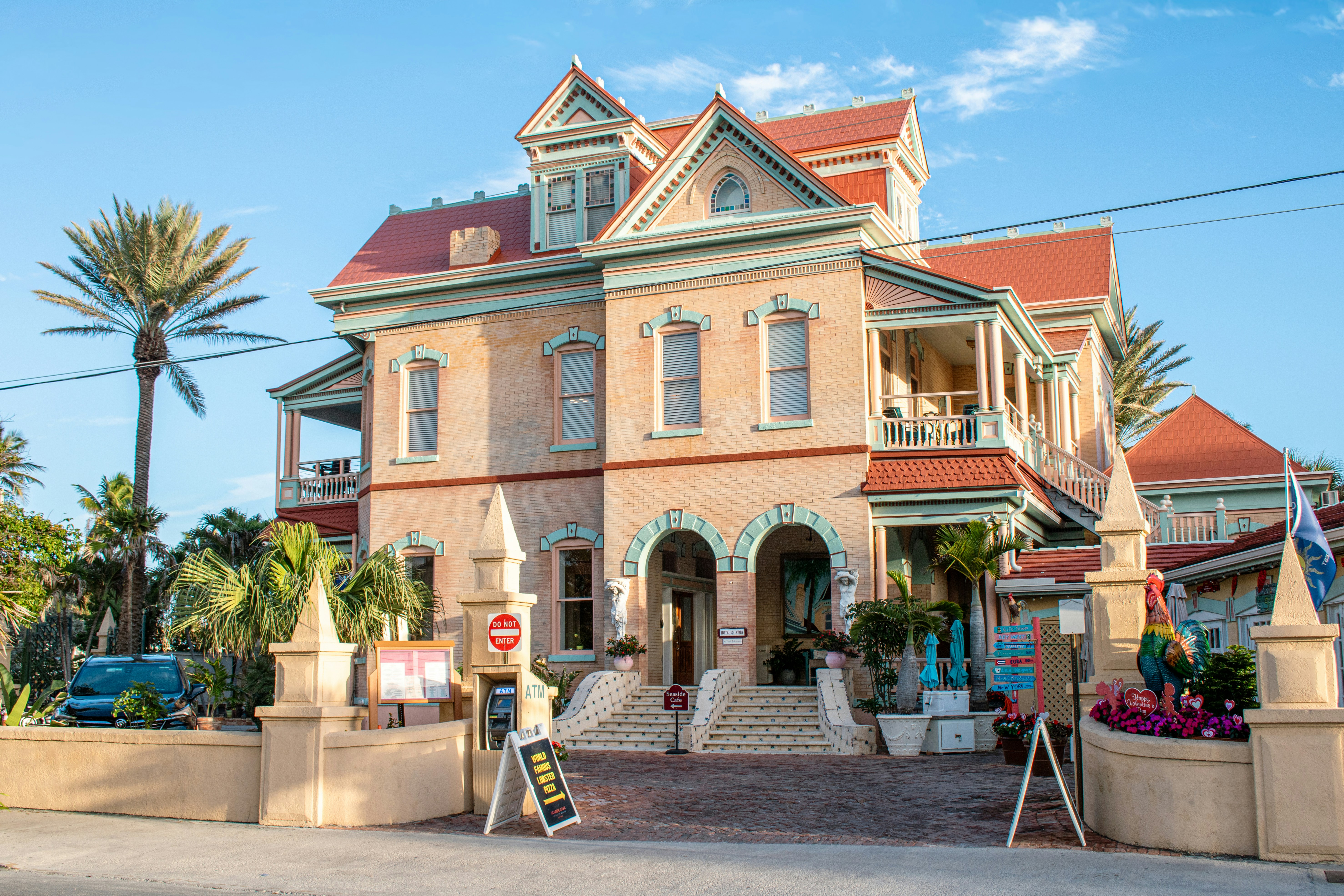 The Laureate Key West hotel in Key West, Florida, USA. | Elaborate victorian house with palm trees and a fence.