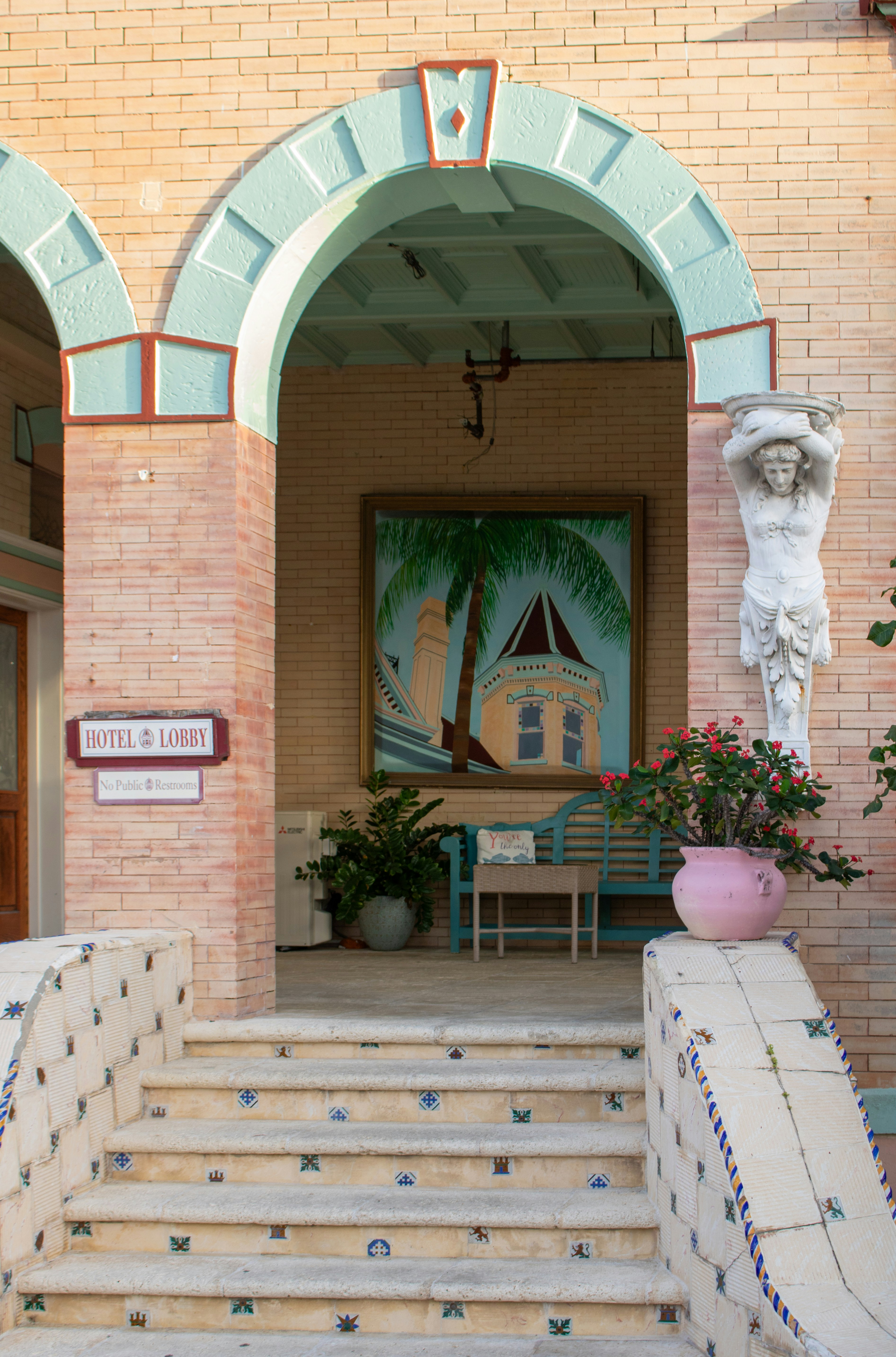 An arched entrance to a hotel lobby | Ornate entrance with tiled stairs and artwork