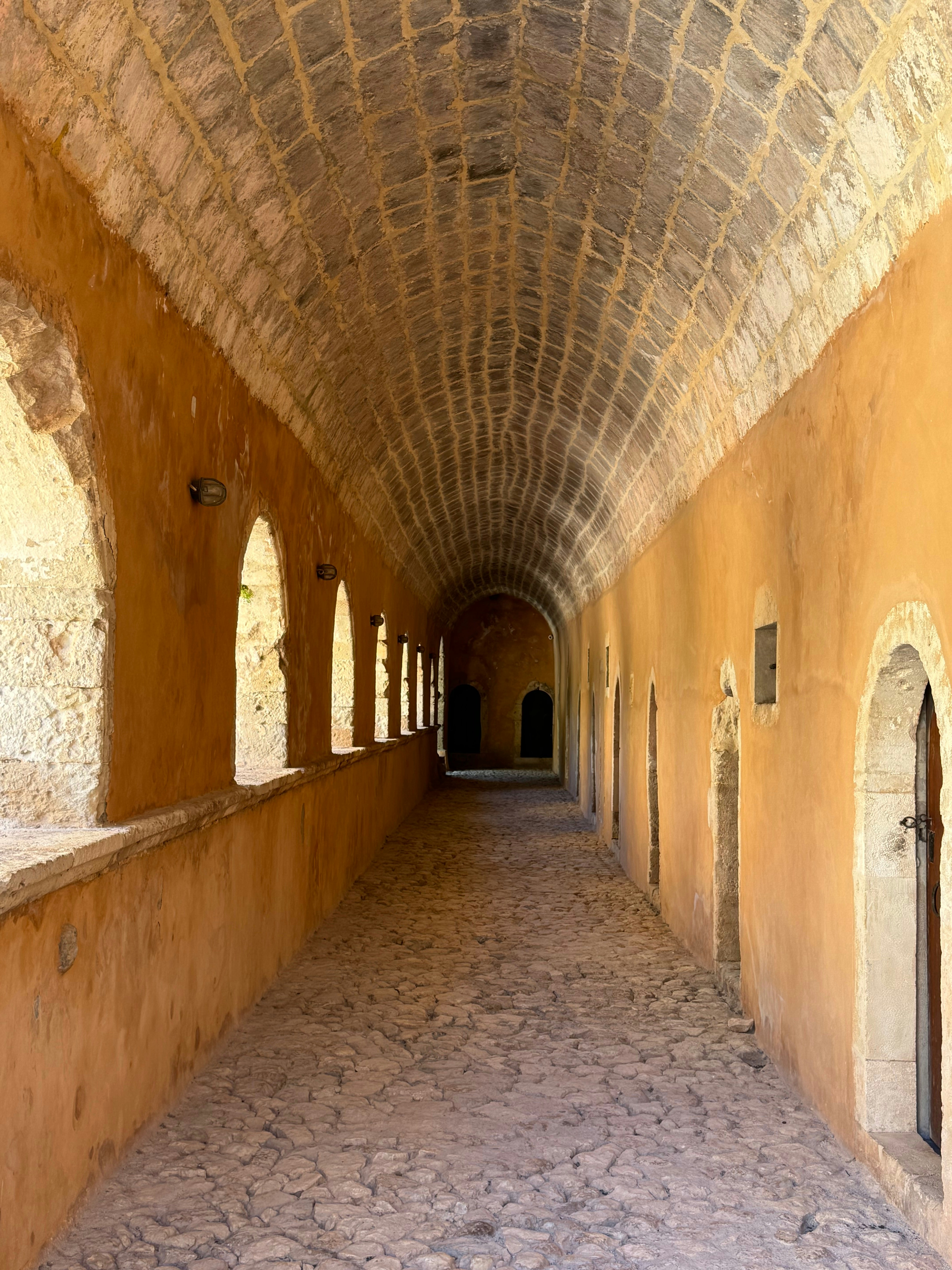 Monastery of Arkadi | Long stone corridor with arched windows and ceiling