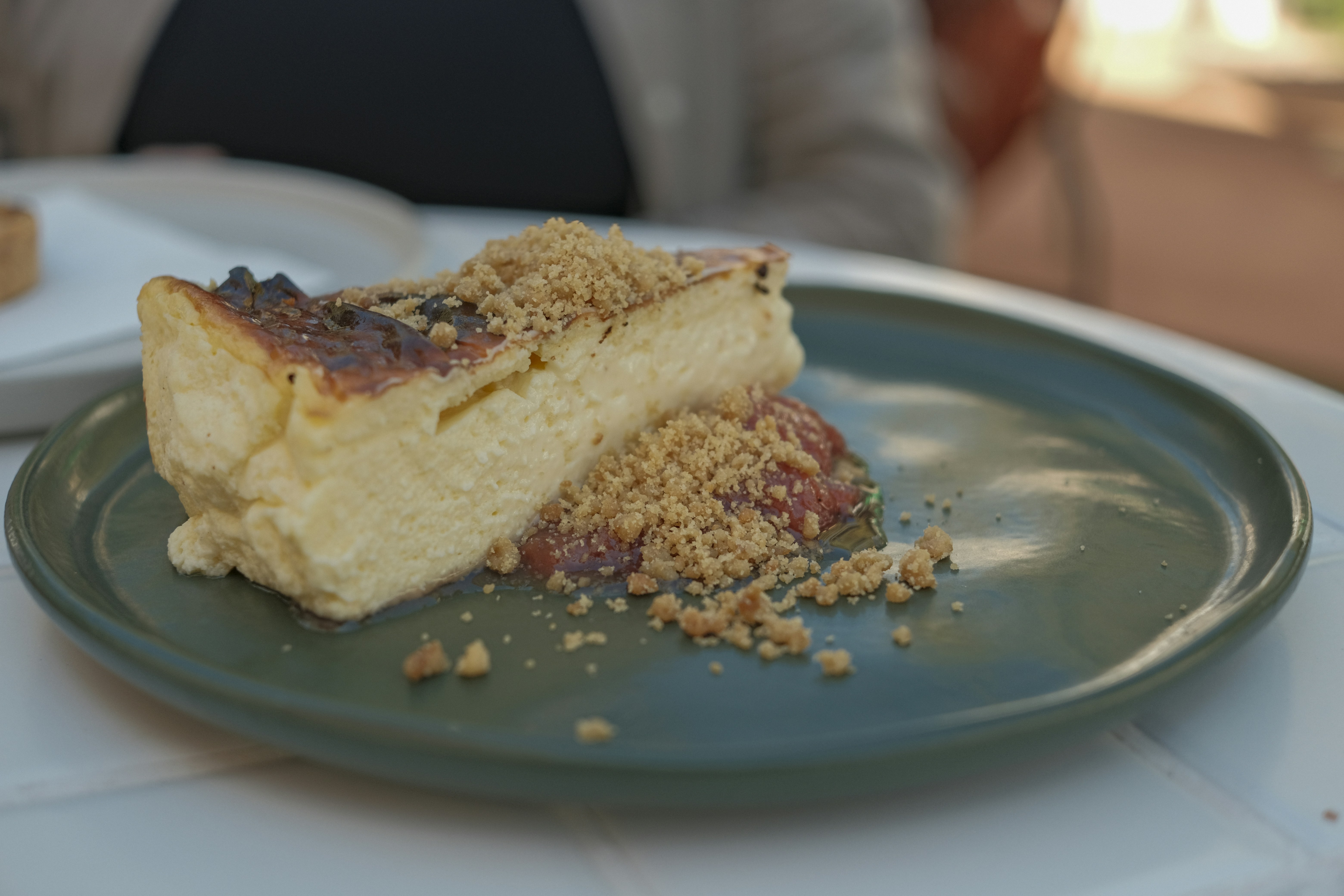 A slice of cheesecake with crumb topping on a plate.