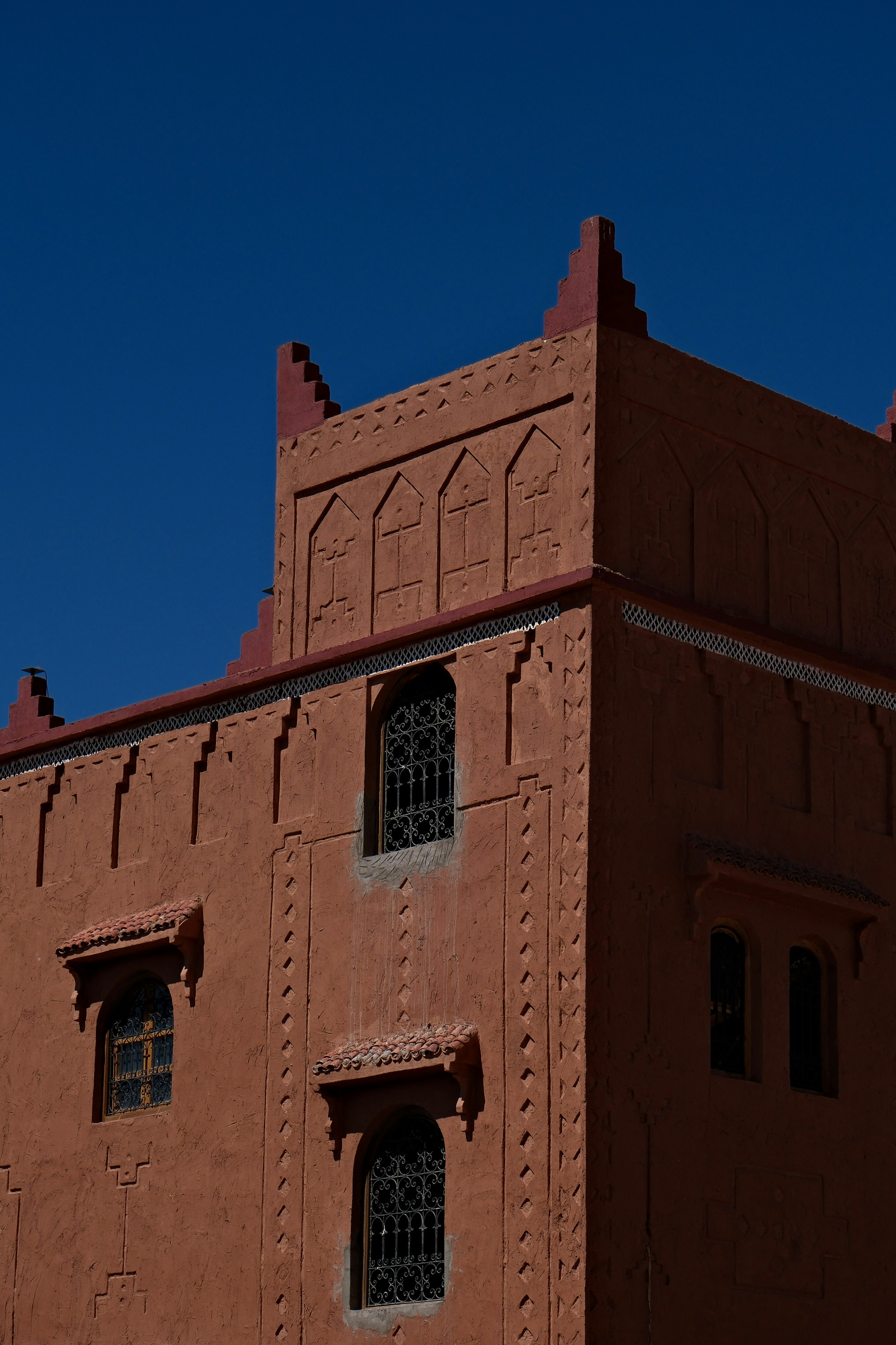 Traditional moroccan building with ornate windows under blue sky