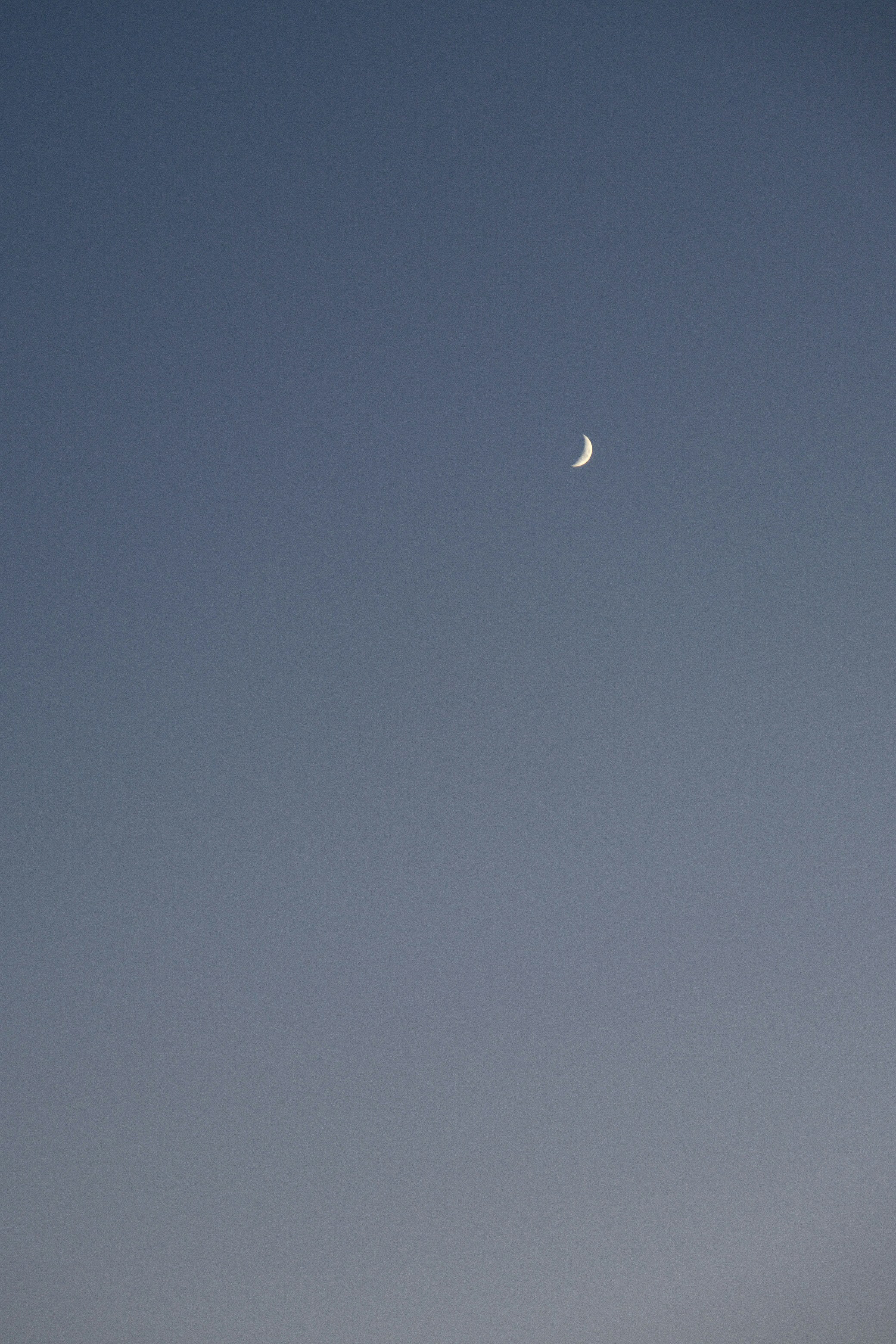 A crescent moon hangs in a dusky sky. photo – Free Space Image on Unsplash