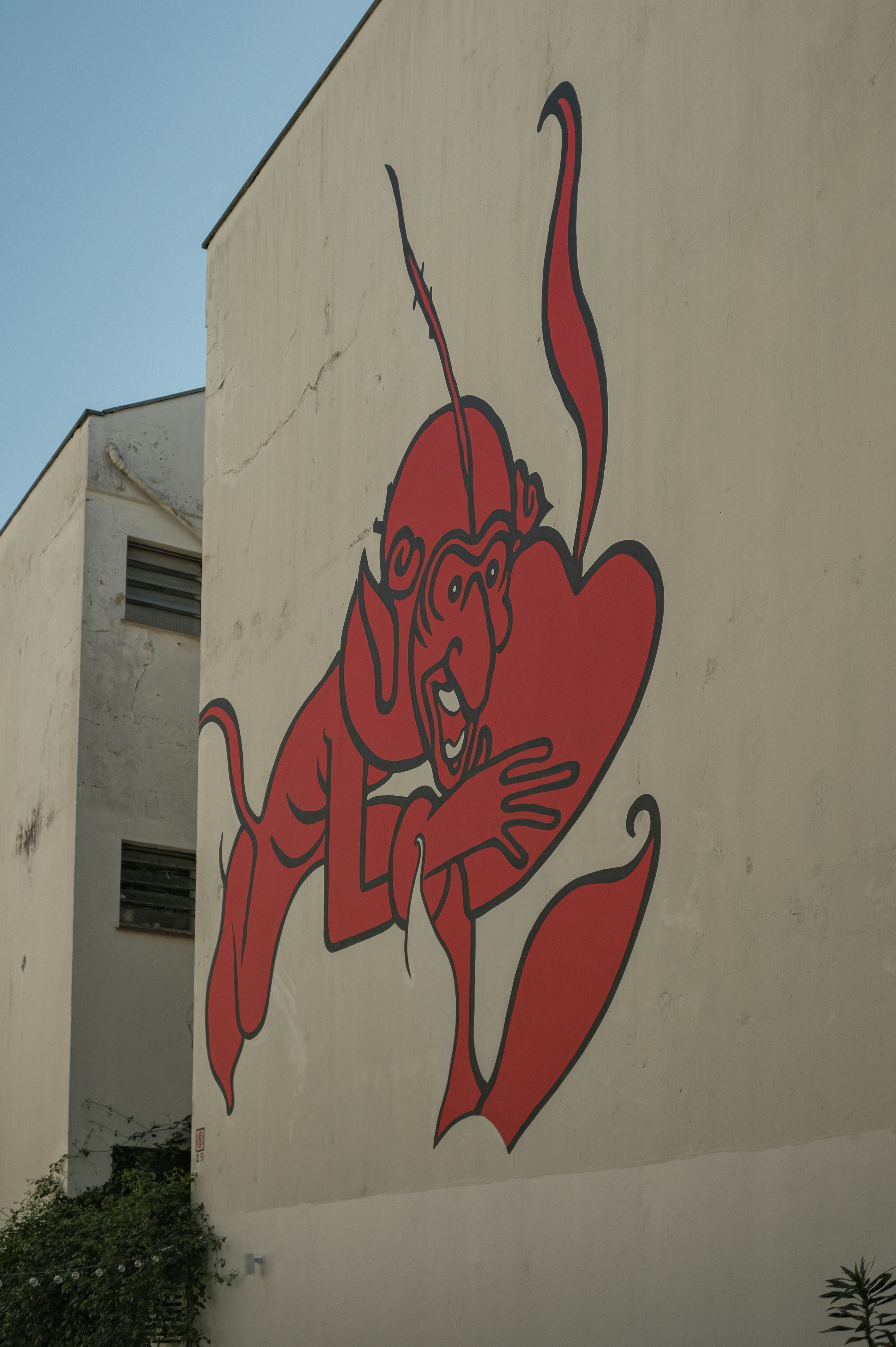 Red cartoon devil character holding a heart on wall