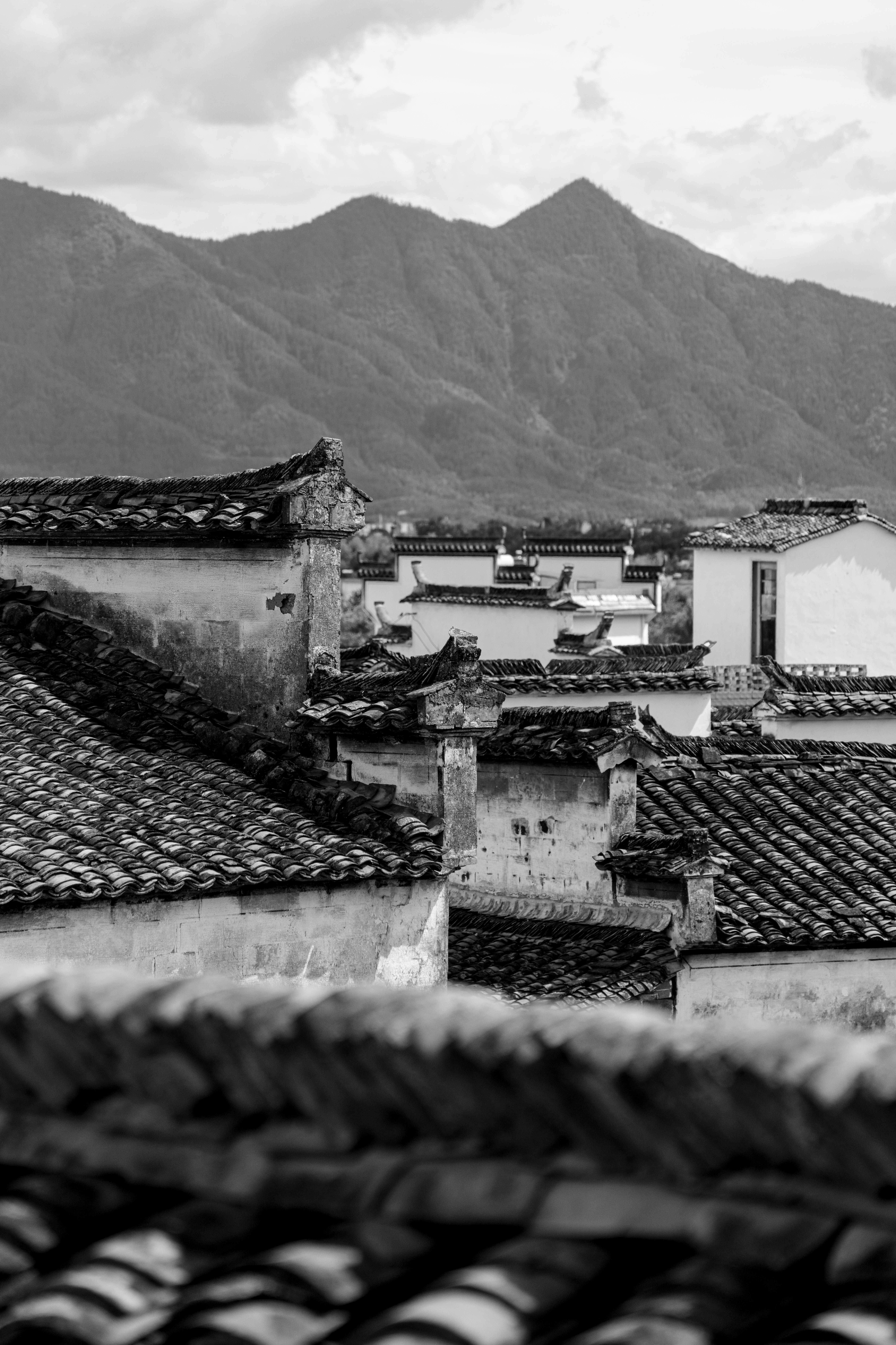 The iconic roof of Chineses Hui Style architectures. | Traditional village rooftops with mountains in background