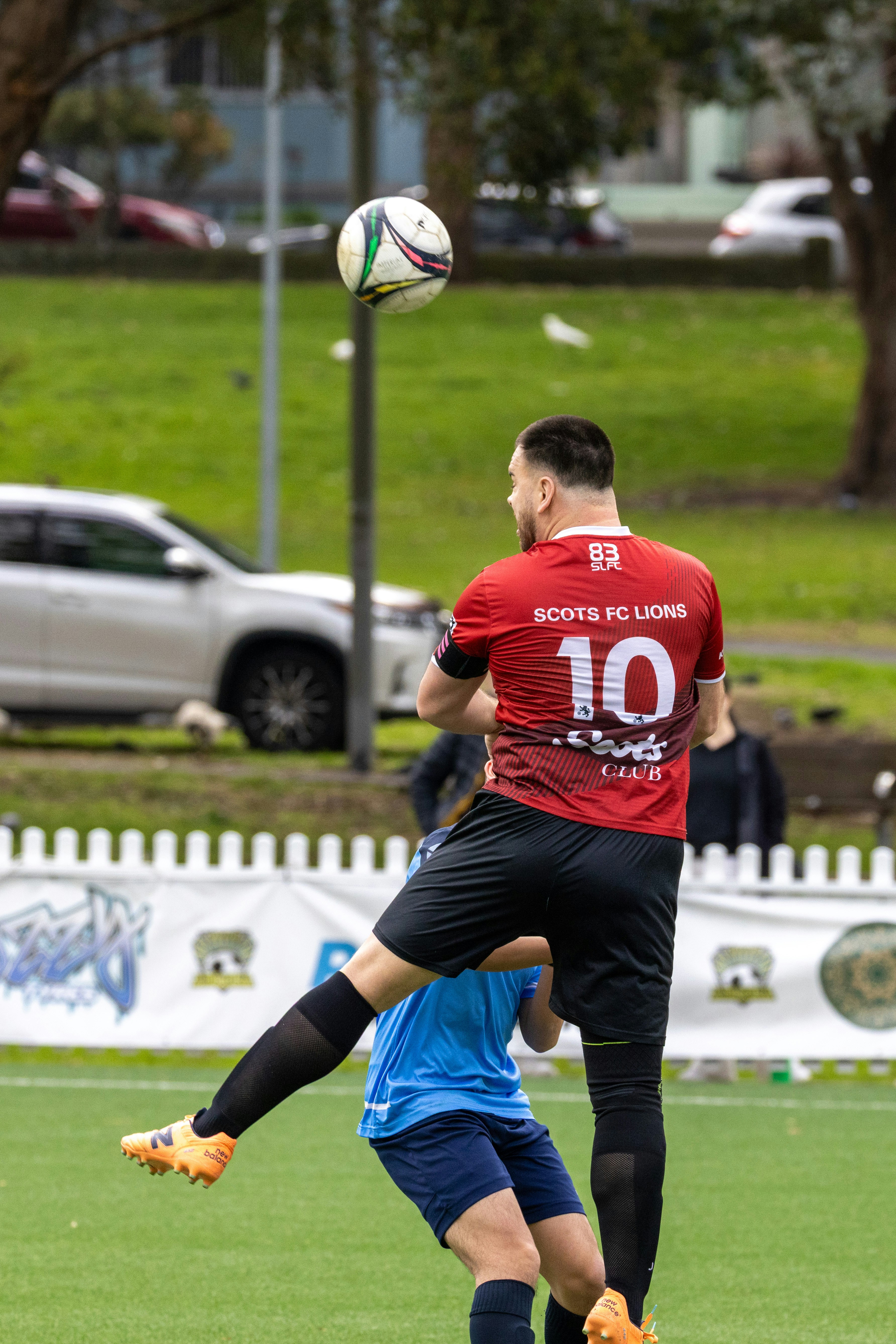 Midair Challenge: Scots FC Lions No. 10 Leaps to Meet the Ball in a Parkside Duel