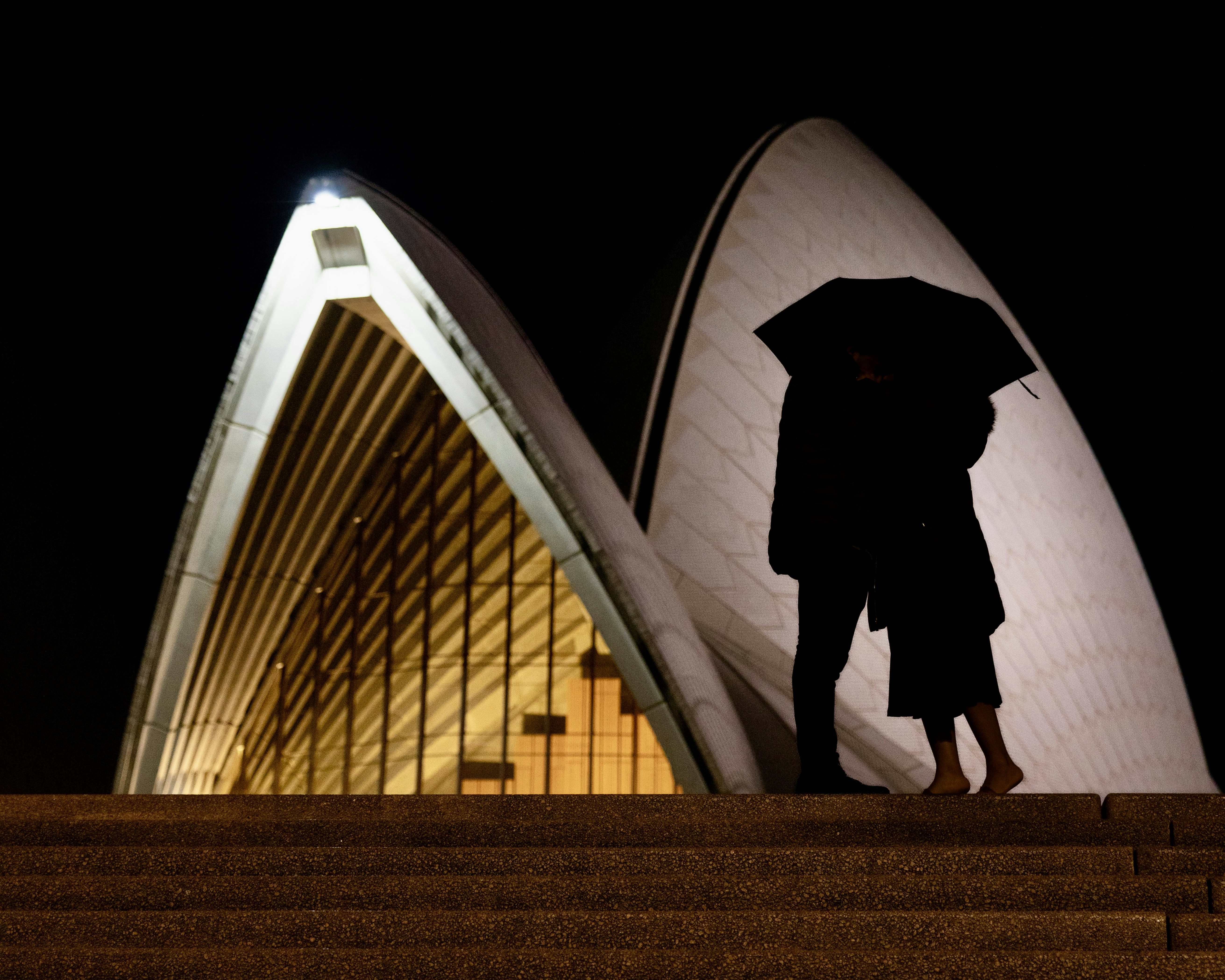 Moonlit Silhouette: Lovers Under Umbrella at the Modern Arch