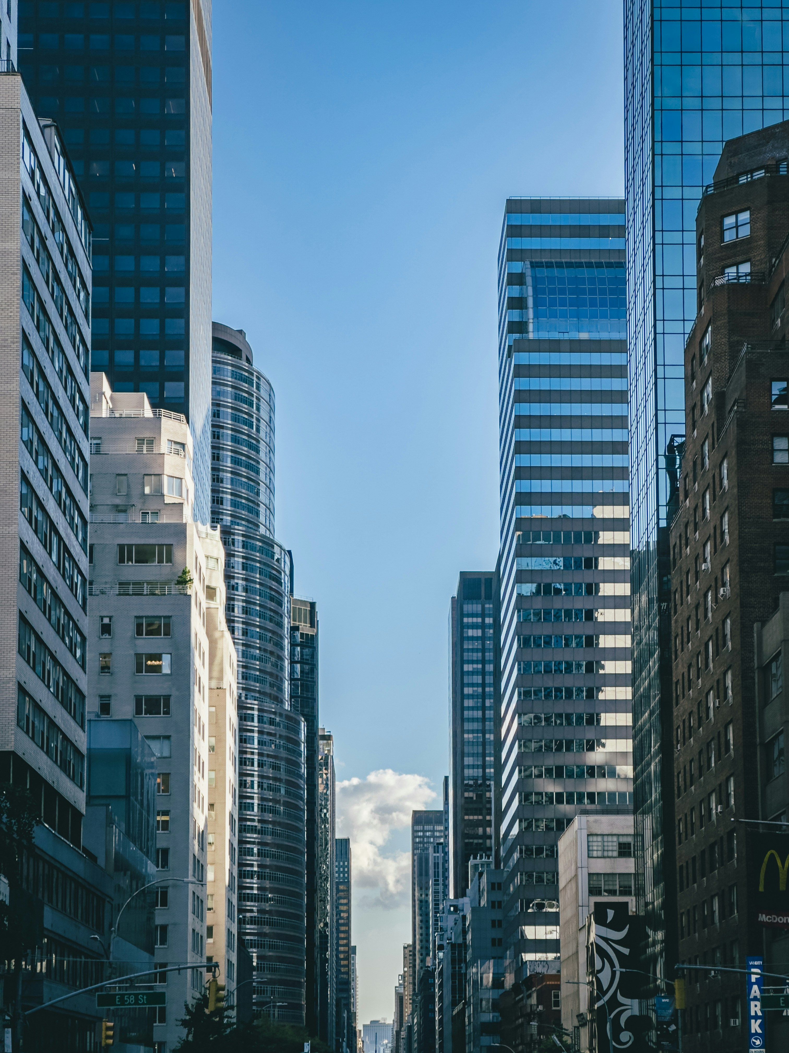 New York City Street. | Tall skyscrapers line a city street under a clear sky.