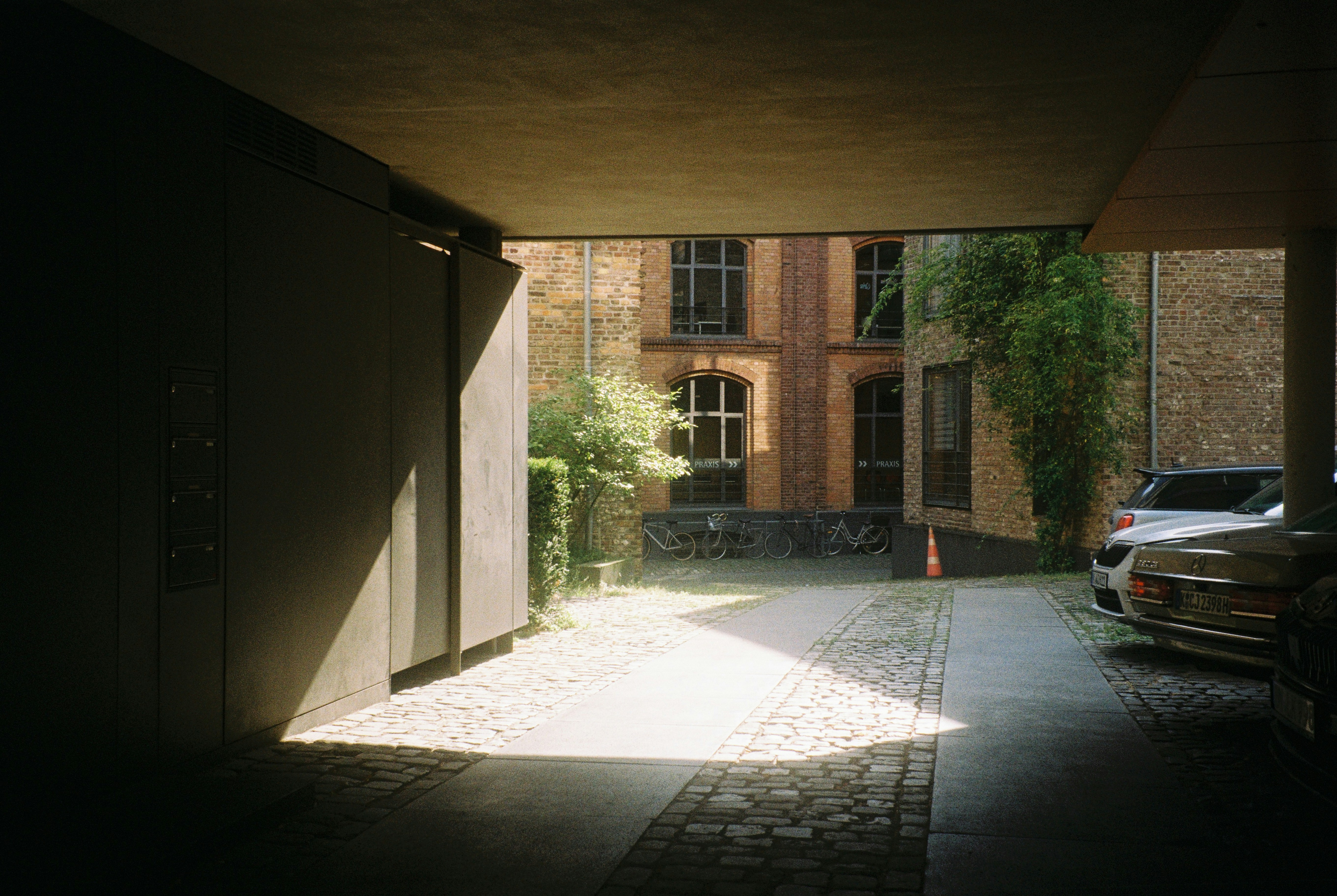 Shot on Kodak Gold 200 | Sunlight streams into a courtyard with brick buildings.