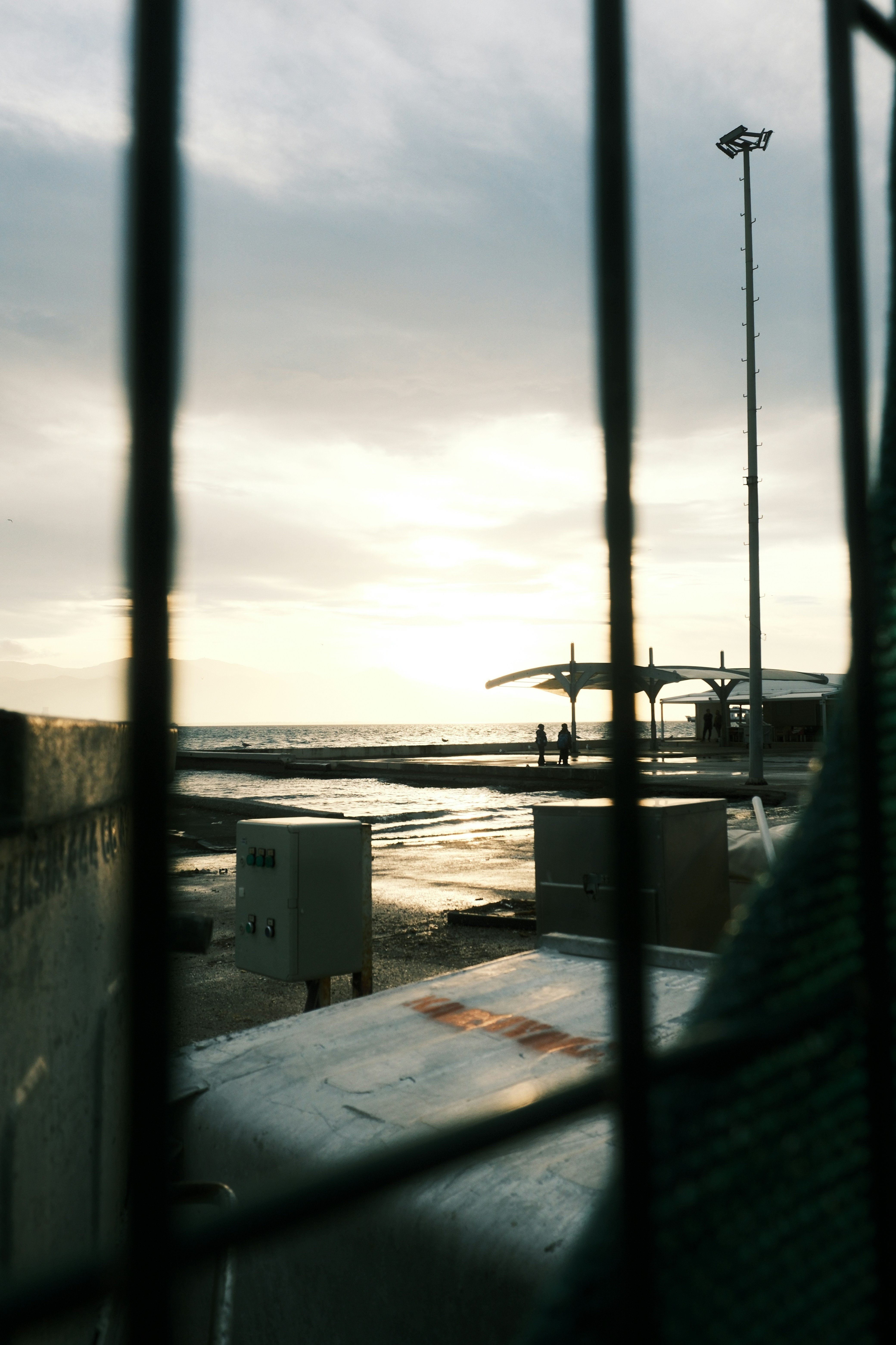 Through the Grate: A Serene Sunset by the Shore