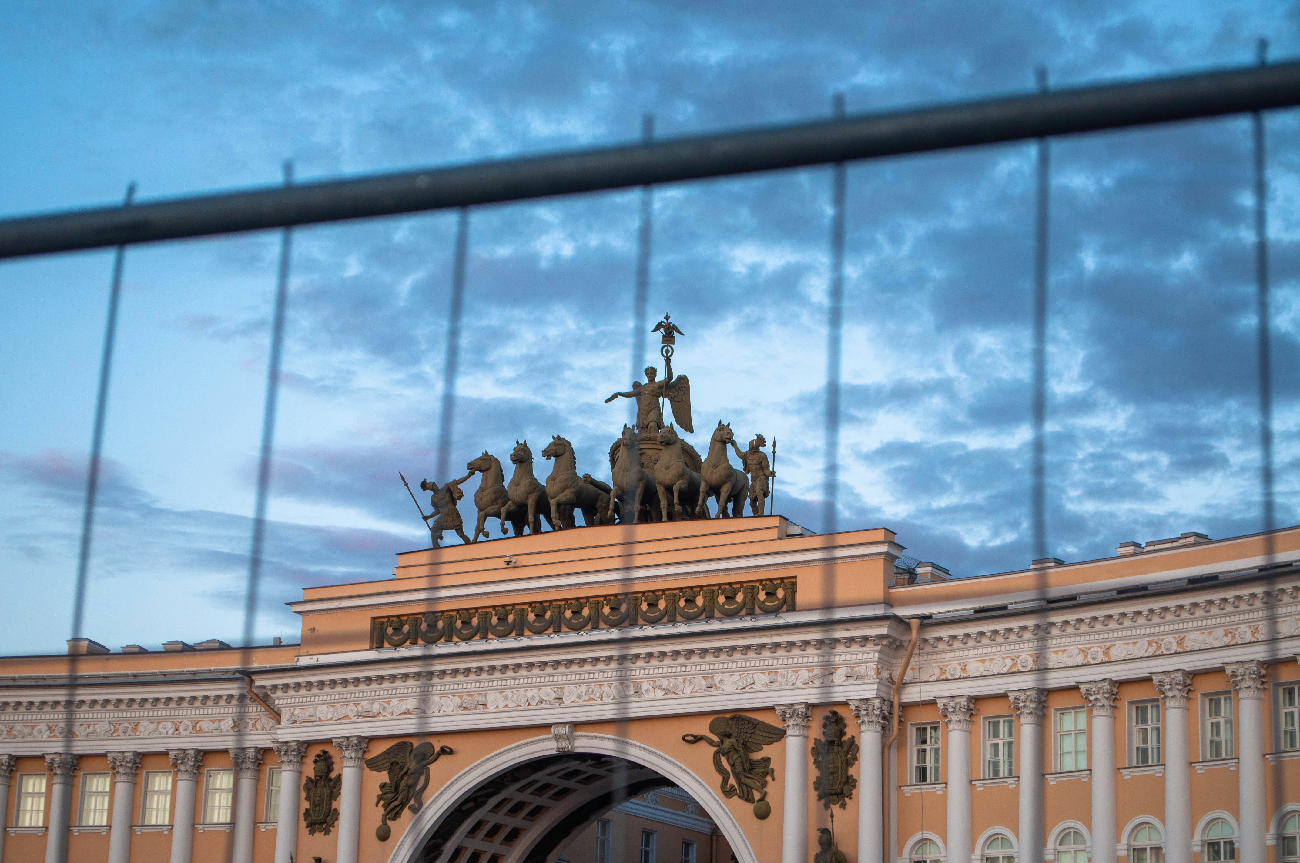 General Staff Building on Palace Square behind a fence, Saint Petersburg, Russia. Night cityscape. St Petersburg's landmark. | Archway with chariot sculpture under cloudy sky