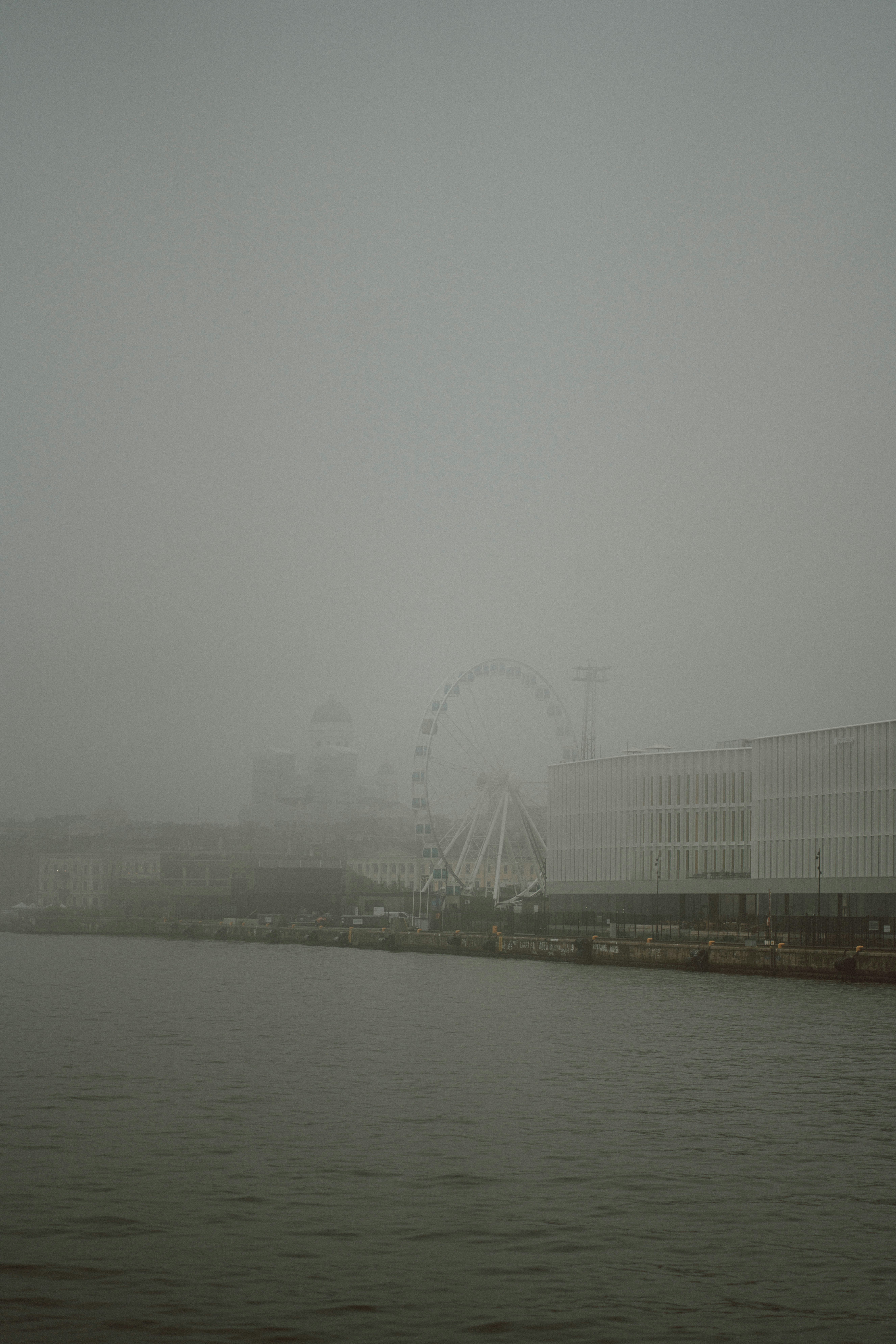 Ferris wheel in a foggy city by the water