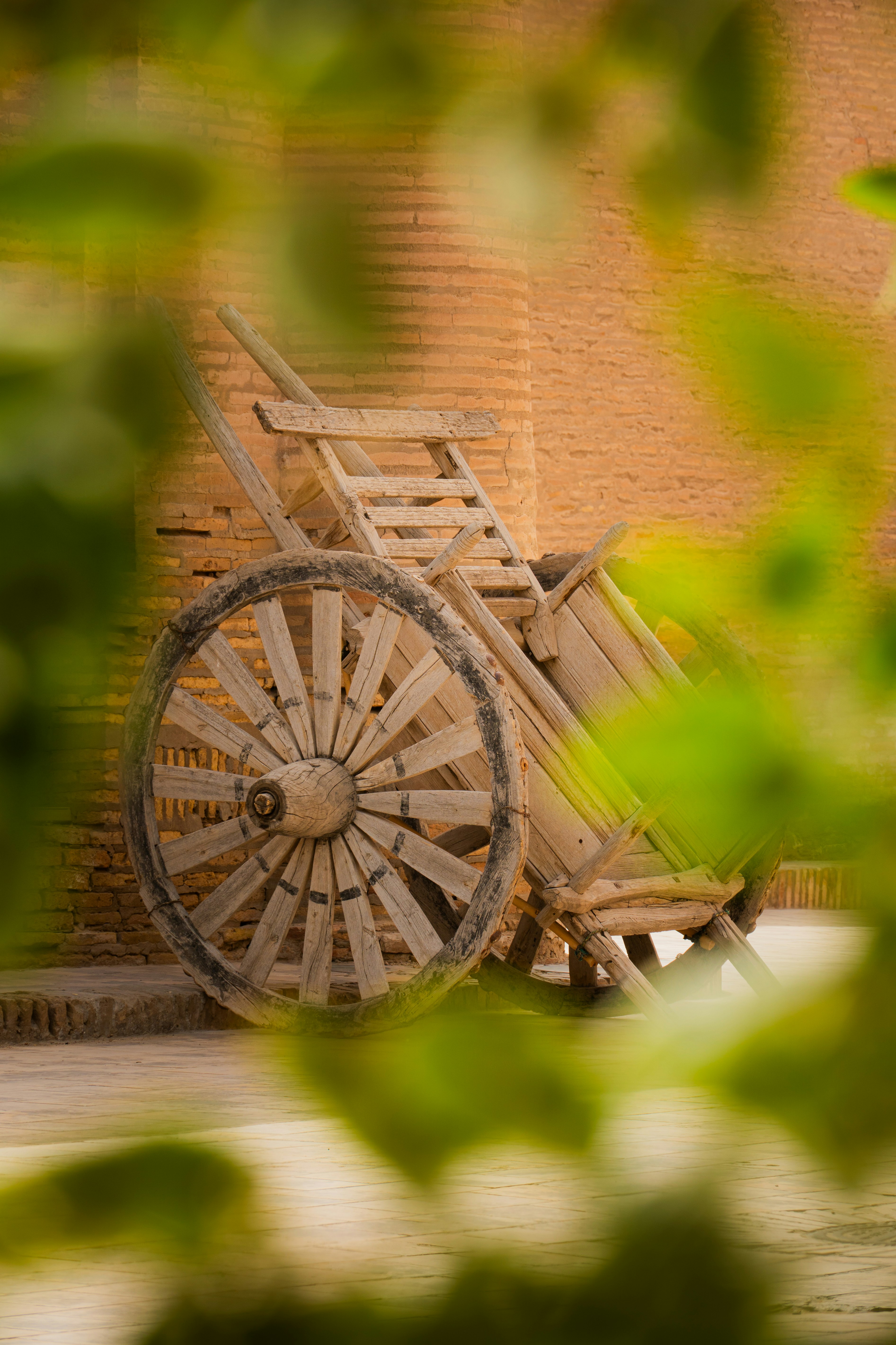 Wheelwright's Echo: A Sunlit Cart Wheel in a Quiet Brick Courtyard