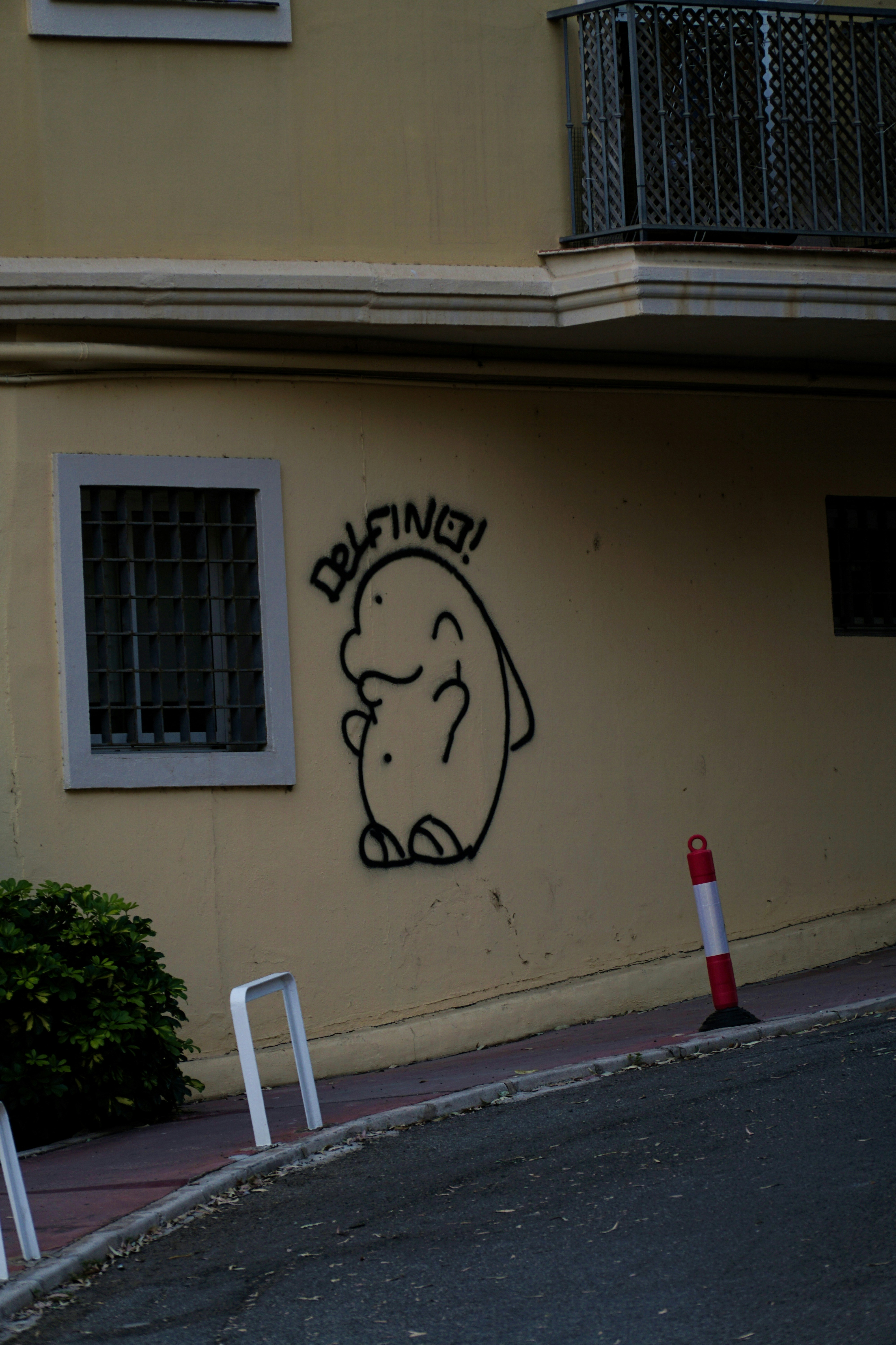 Graffiti of a cartoon dolphin on a yellow wall.