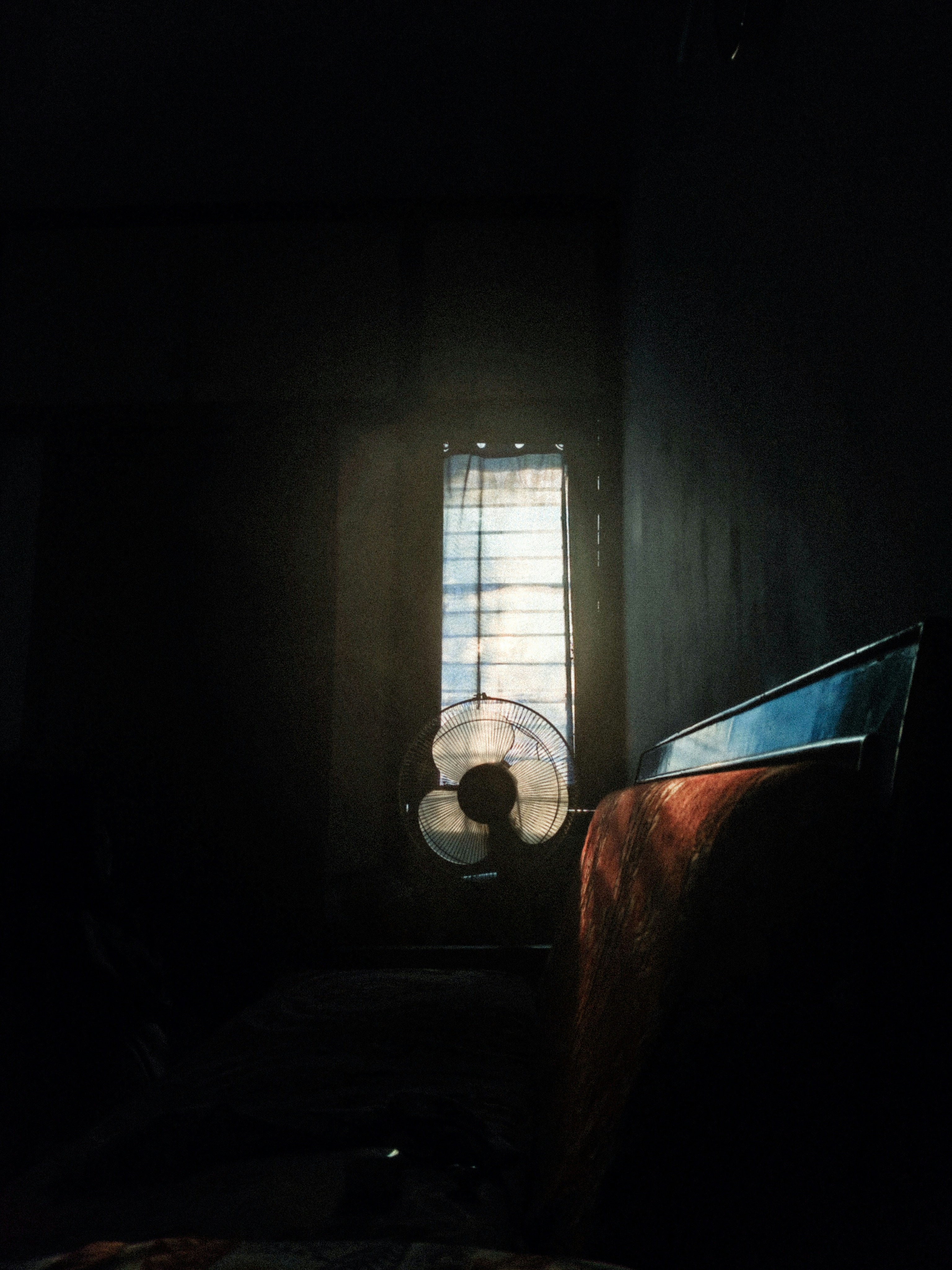 26mm | f1.8 | ISO- 100 | 1/25s | A fan is silhouetted against a bright window.
