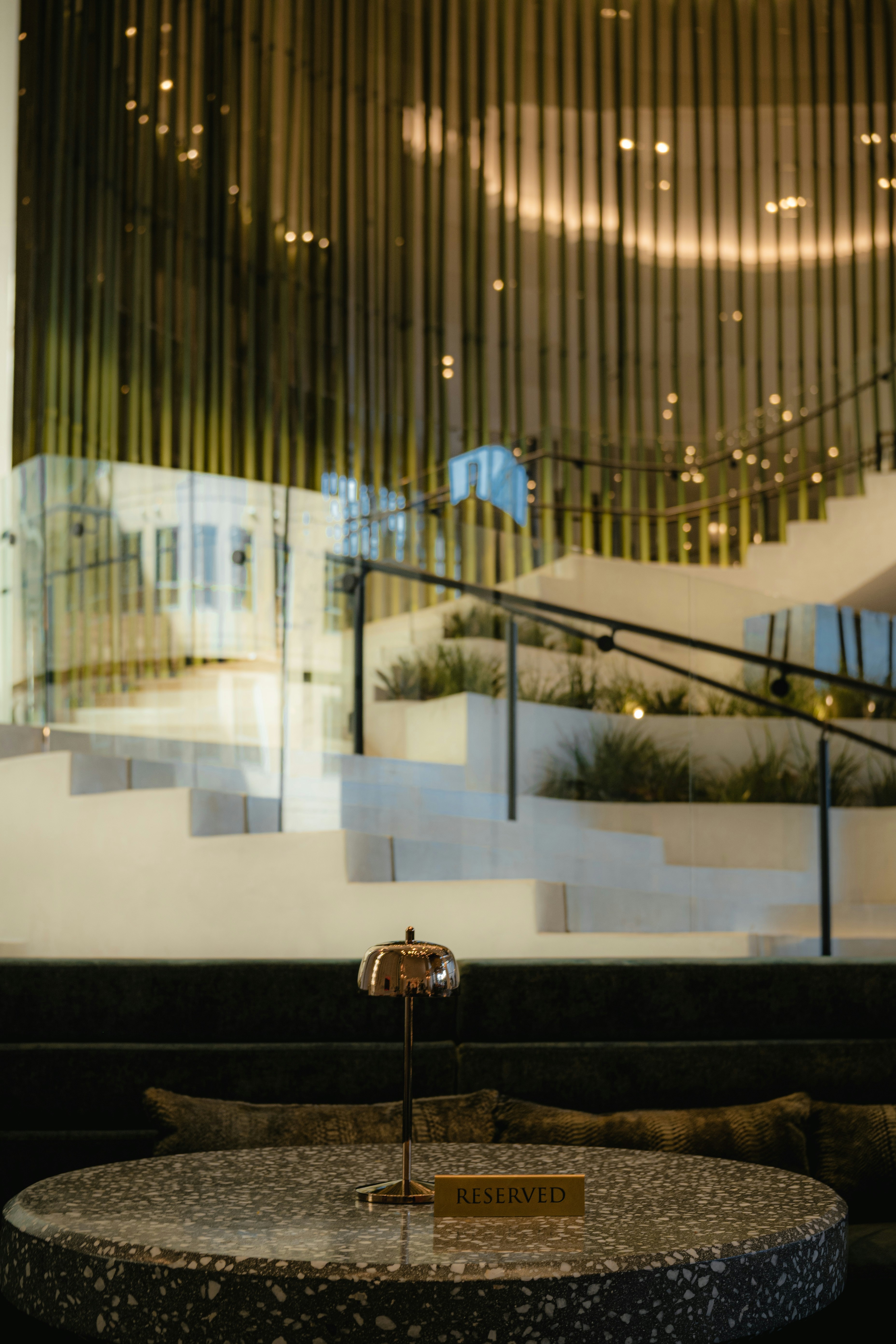 A polished table with a reserved sign and a stylish lamp, framed by an elegantly designed staircase and ambient lighting in a modern interior space.