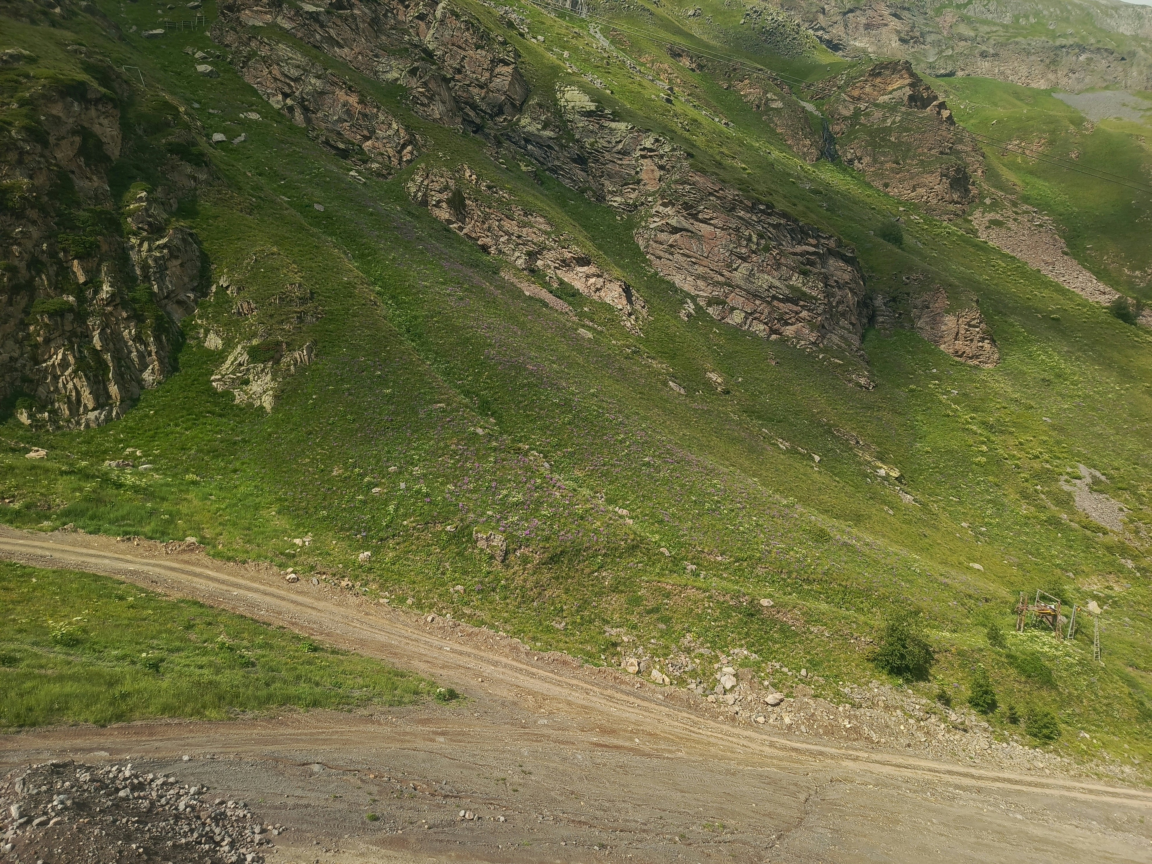 Lush green hillsides adorned with rocky outcrops under a clear sky, showcasing the beauty of natural landscapes.