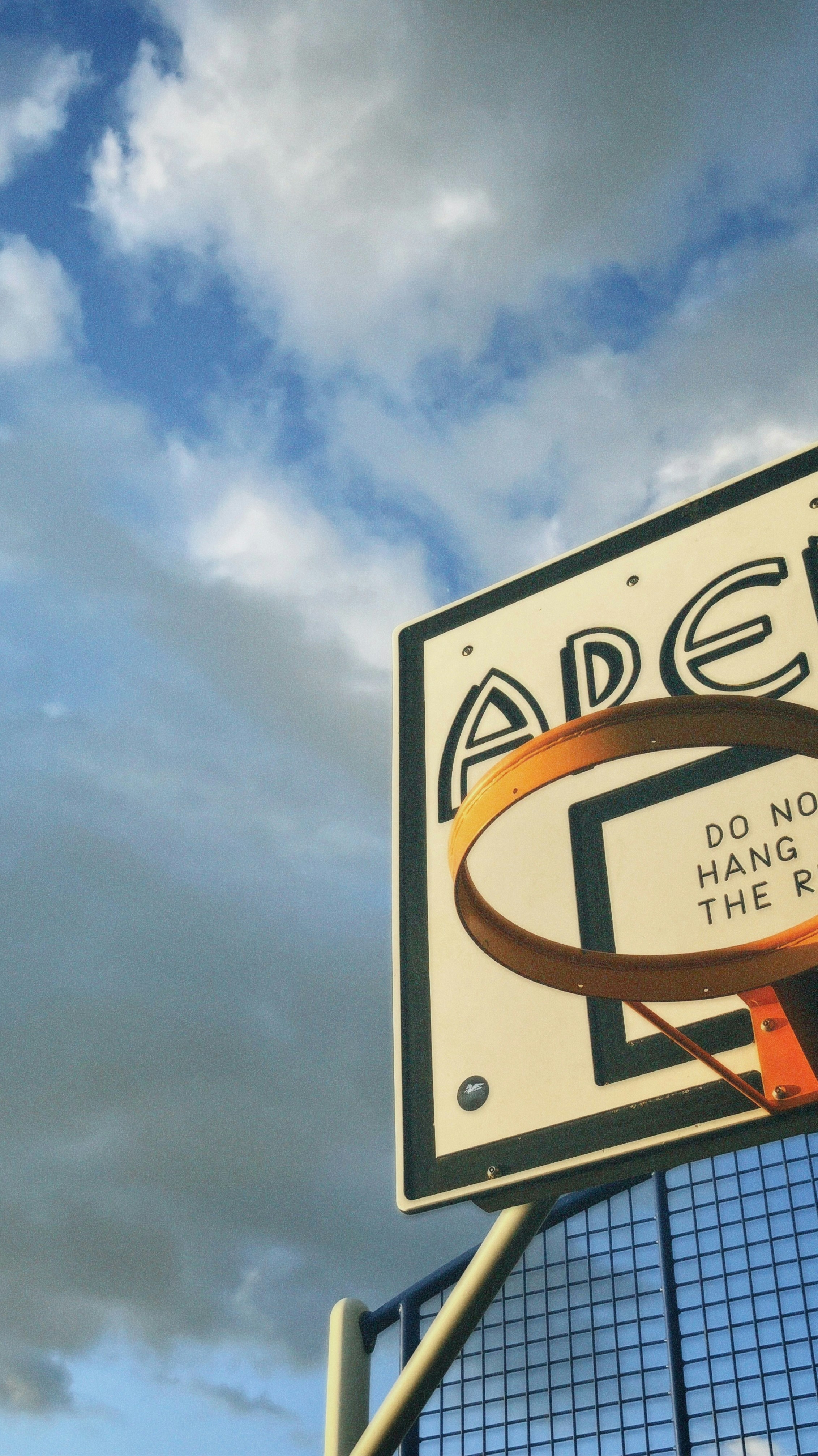 Basketball Hoop Framed by Sky and Sign