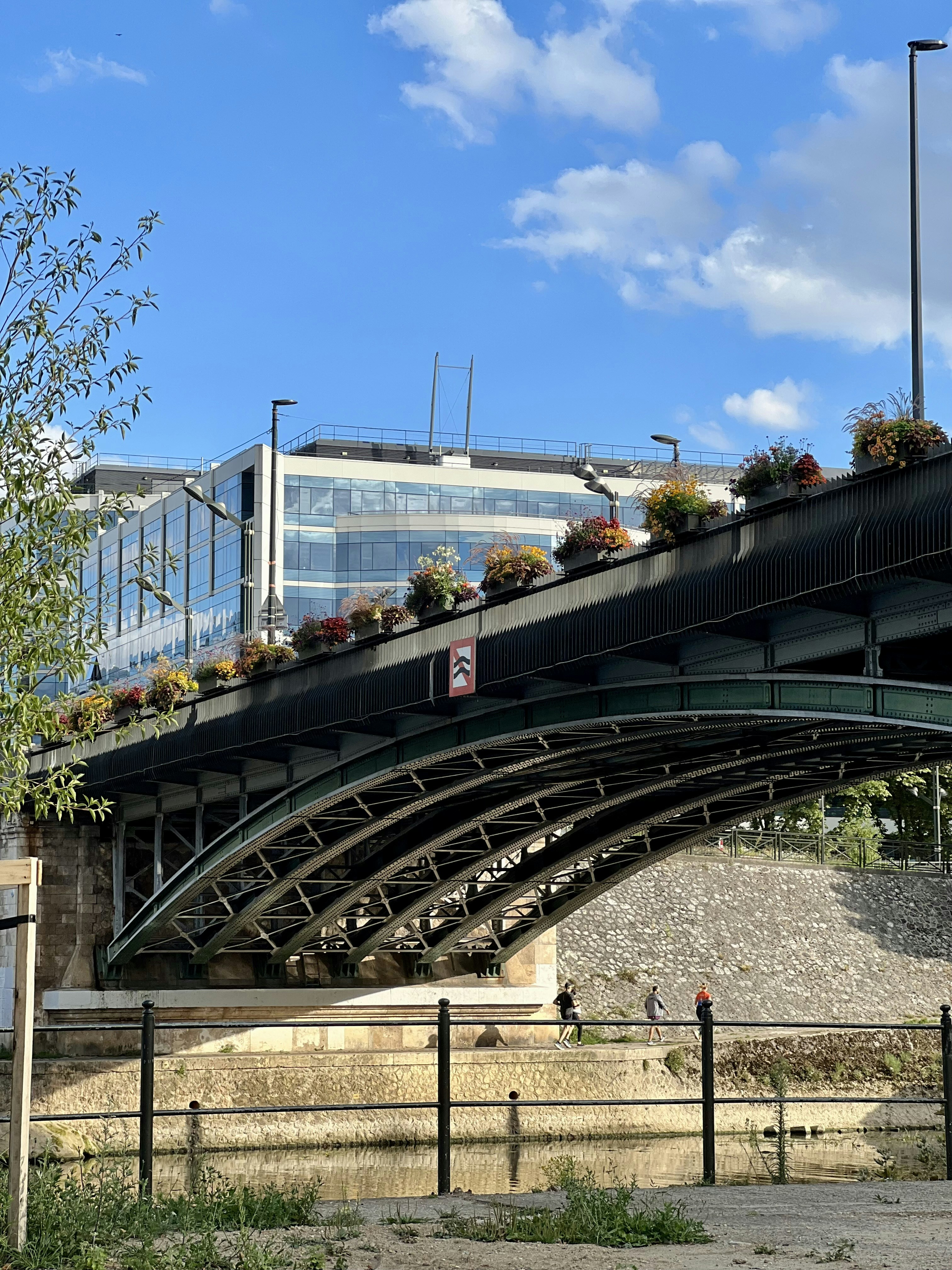 Floral Promenade Above Steel Arches: A Riverfront Scene with Glass and Flower Boxes
