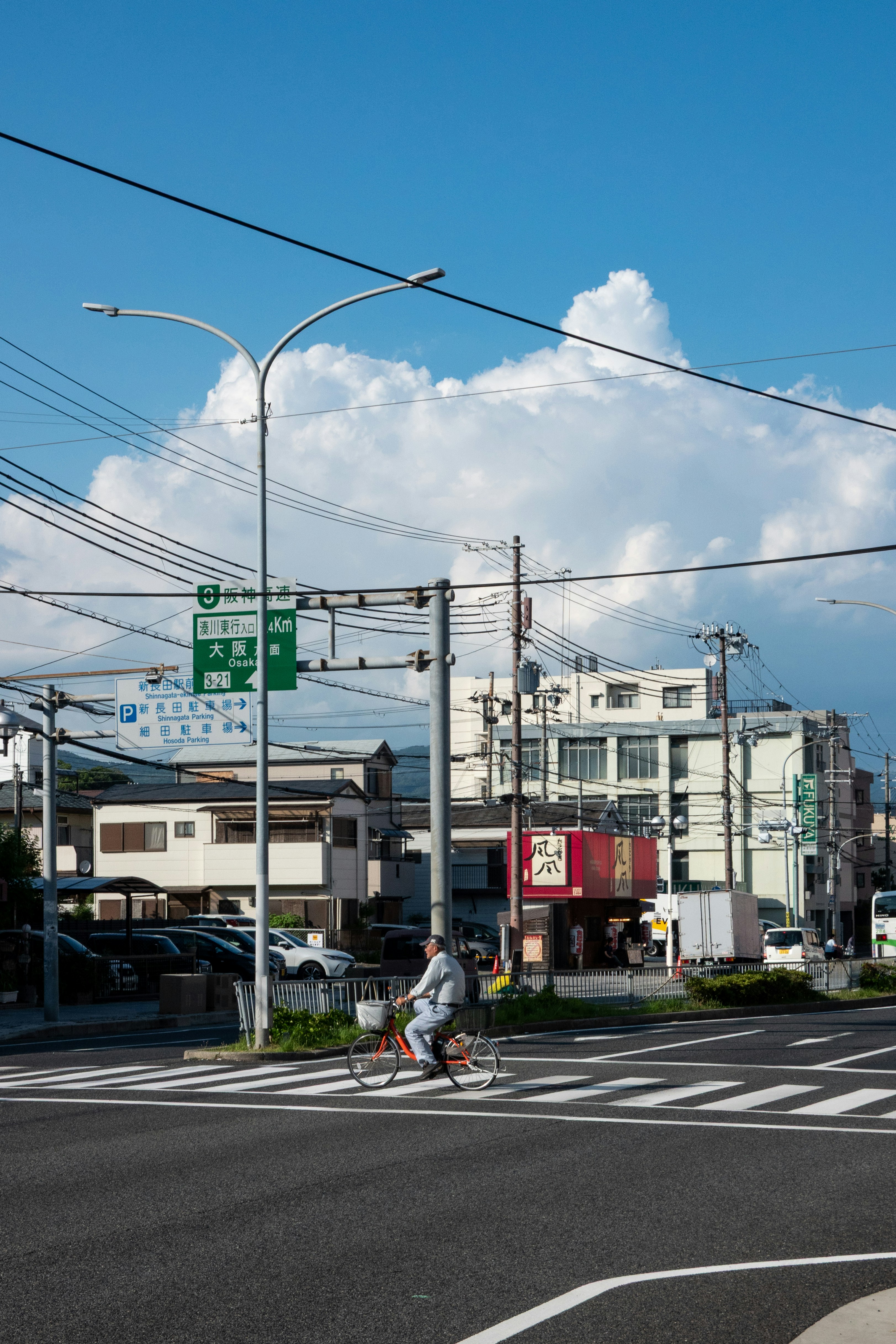 Person riding bicycle at intersection with buildings.