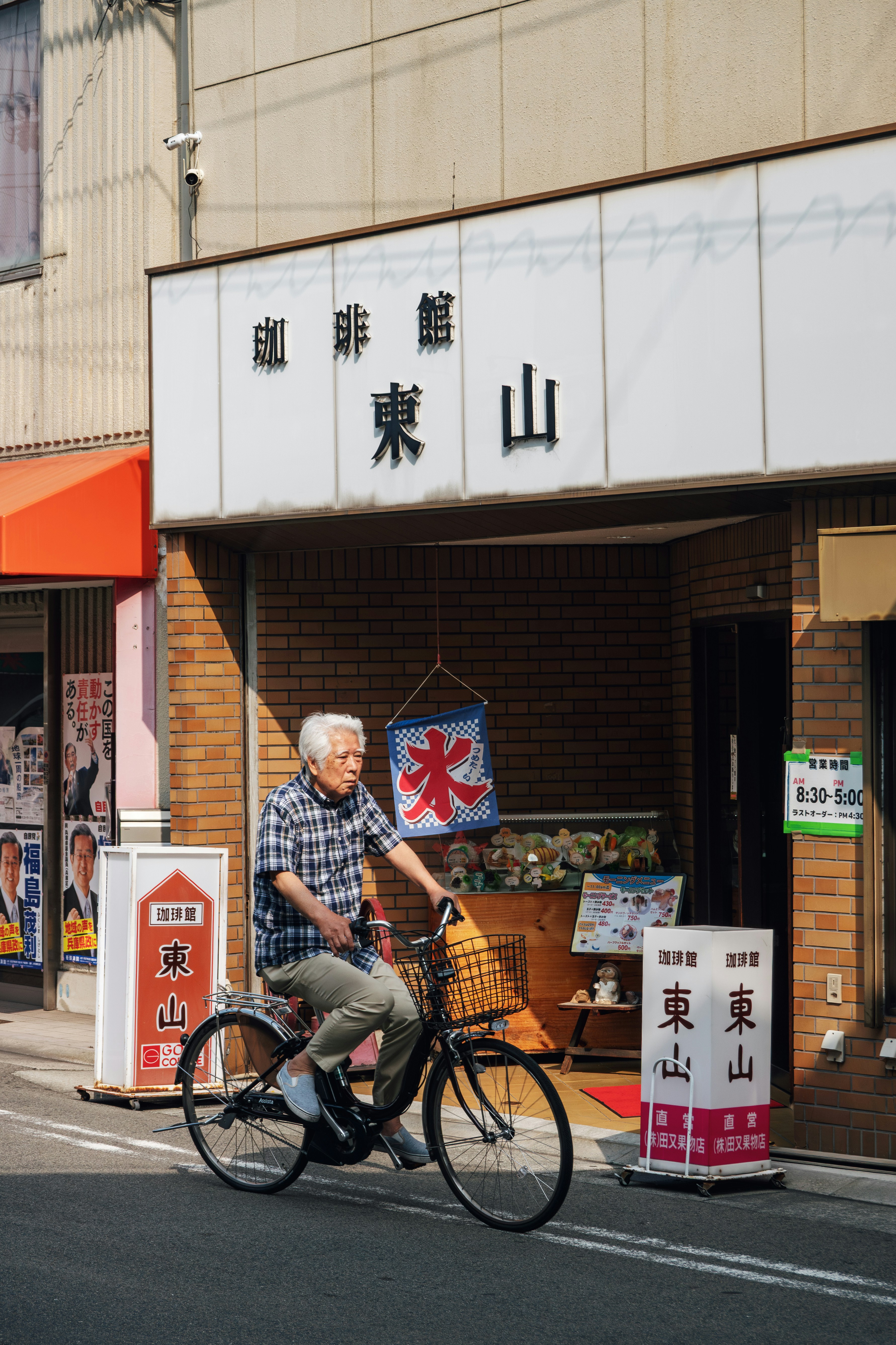 Elderly man rides bicycle past storefront in japan. photo – Free Street ...