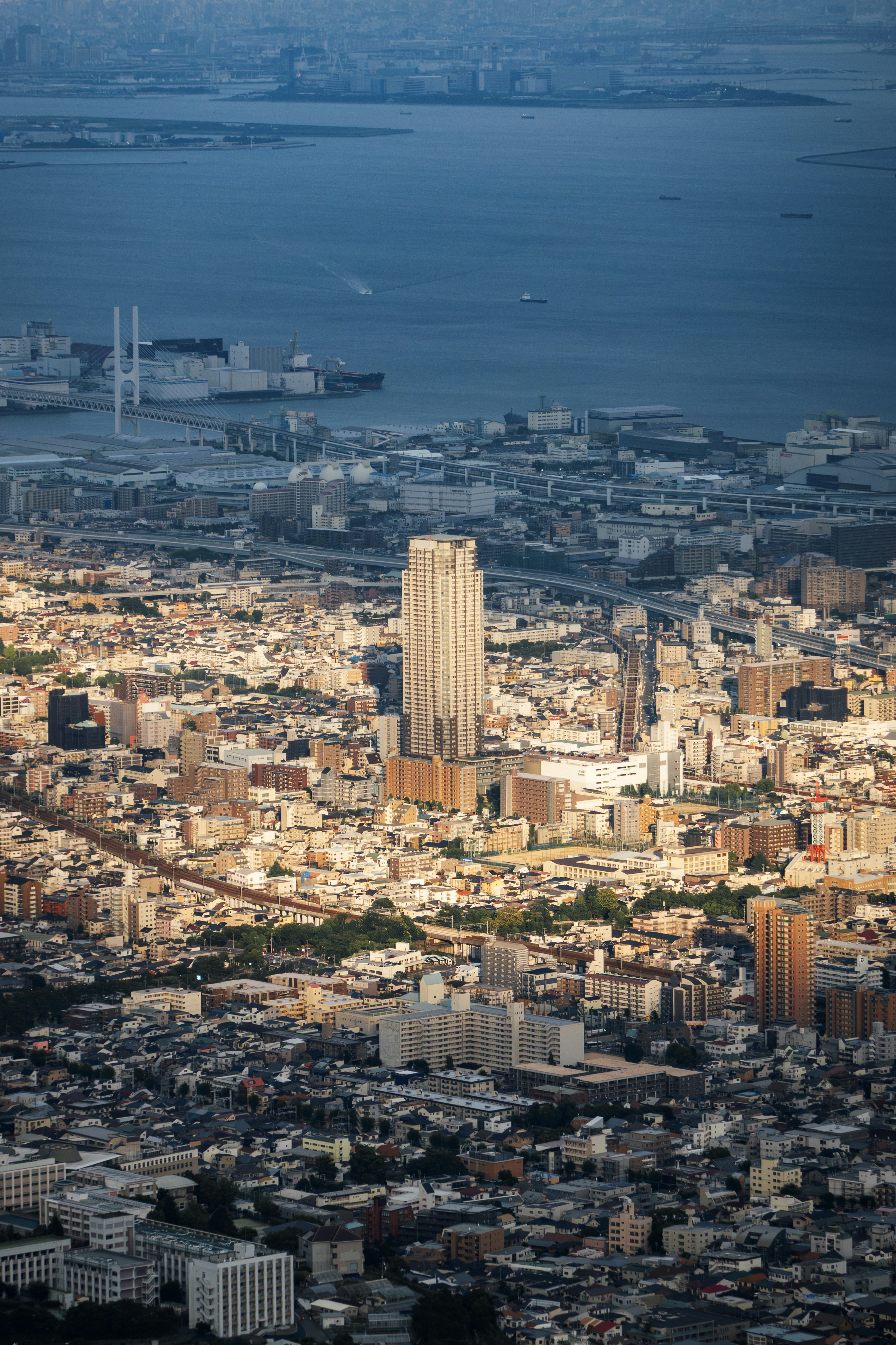 Aerial view of a bustling city with a prominent skyscraper amidst a patchwork of urban structures, showcasing the blend of modernity and tradition. 