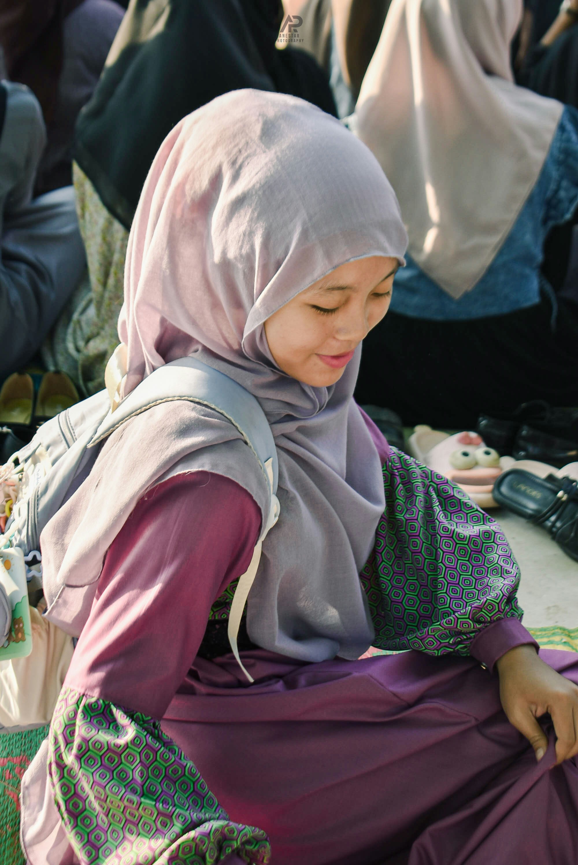 Young woman in a hijab and purple dress smiles