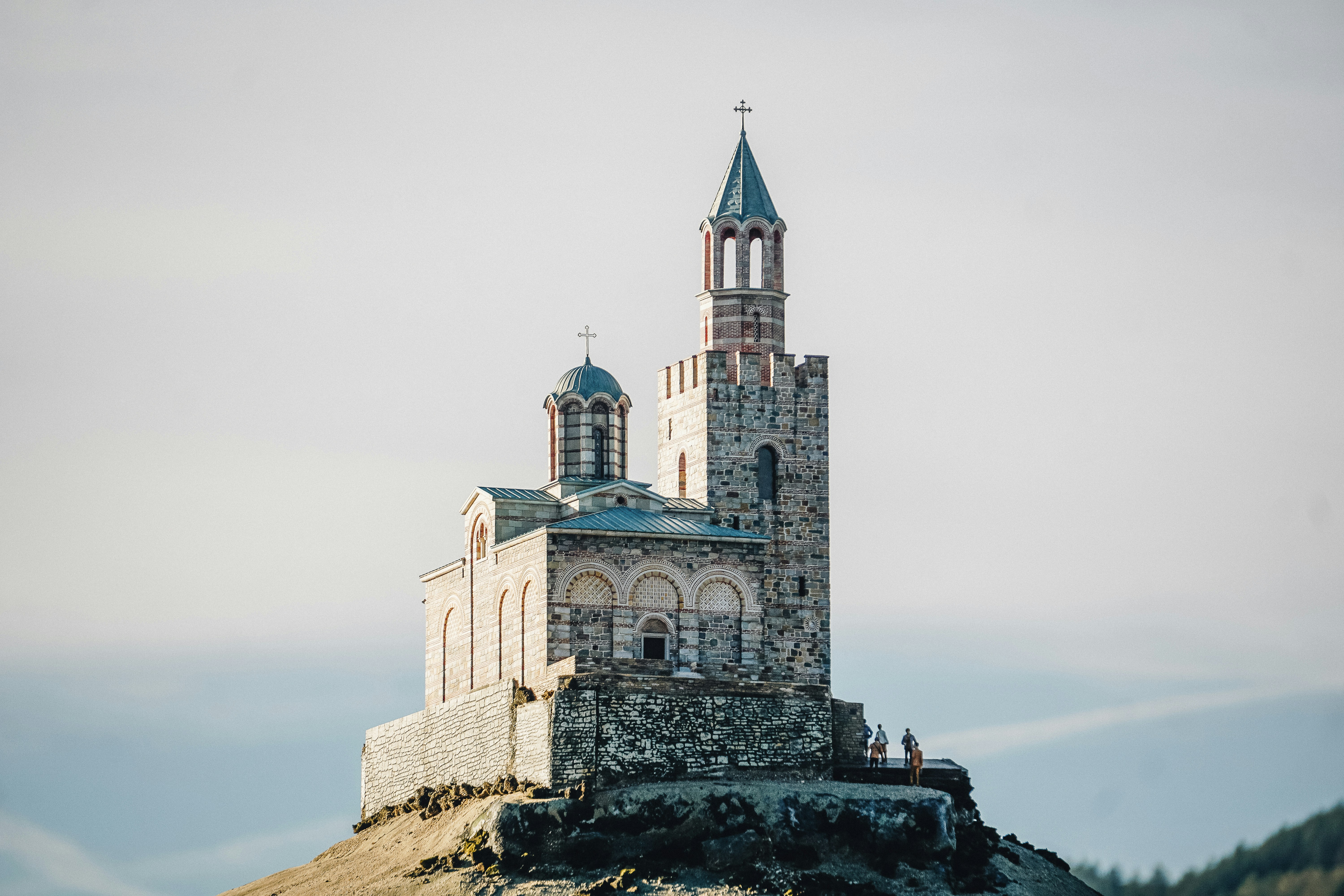Historic church perched atop a rocky outcrop, surrounded by a serene landscape. The architecture showcases intricate details and a harmonious blend with nature.