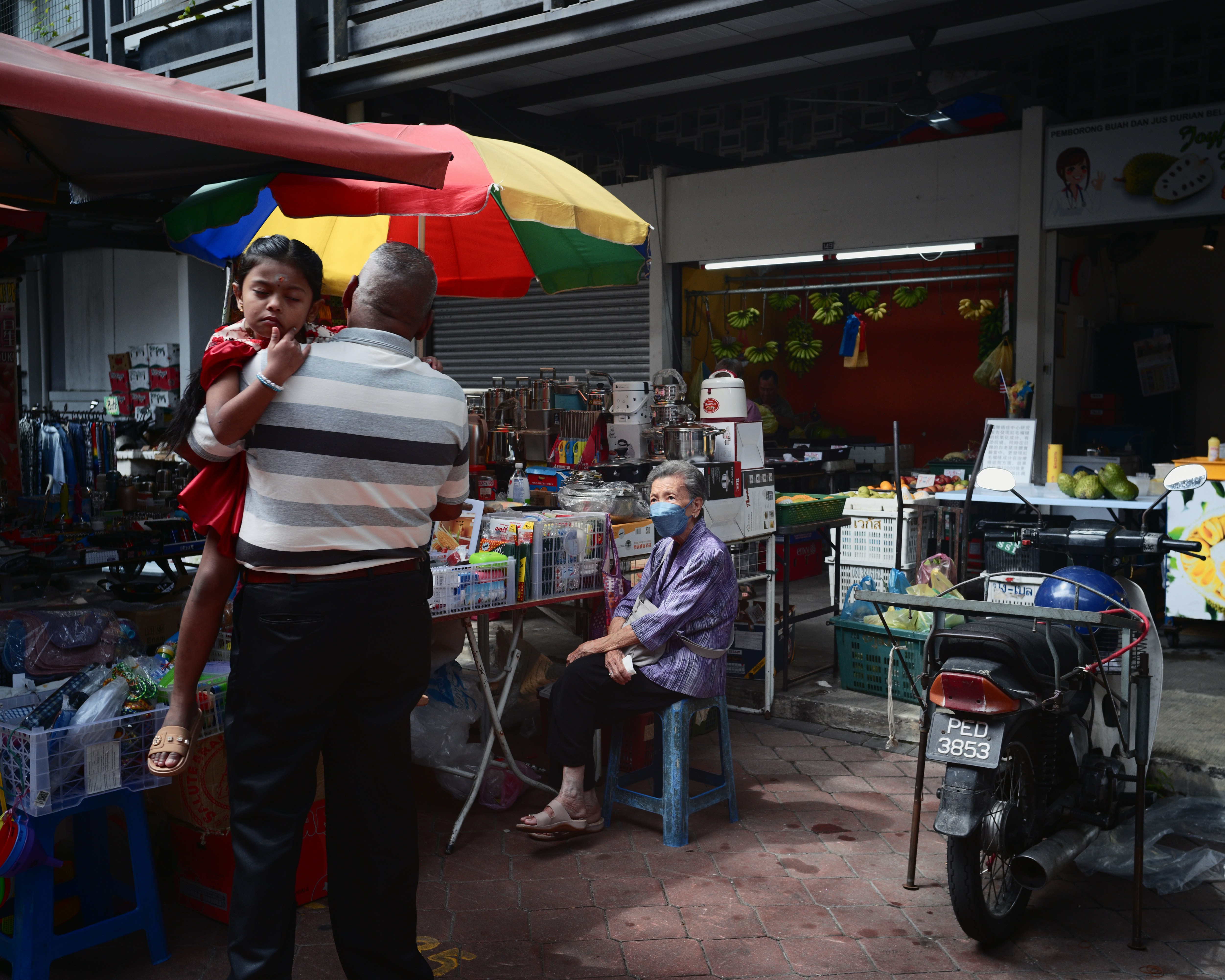 Under the Multicolored Umbrella, A Quiet Exchange at a Street Market