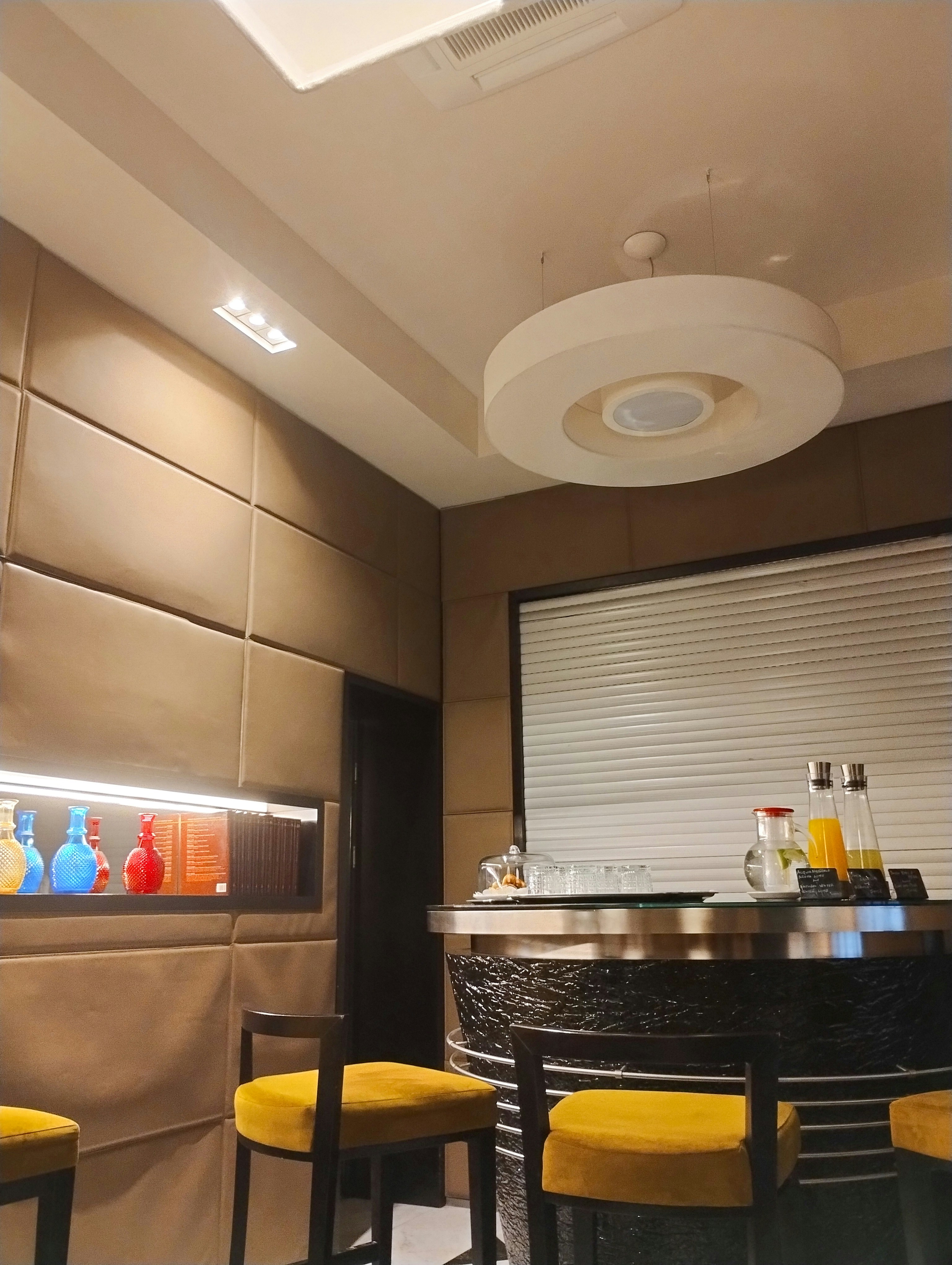 A bar in a hotel in Rome, Italy. | Modern bar area with yellow stools and colorful bottles.