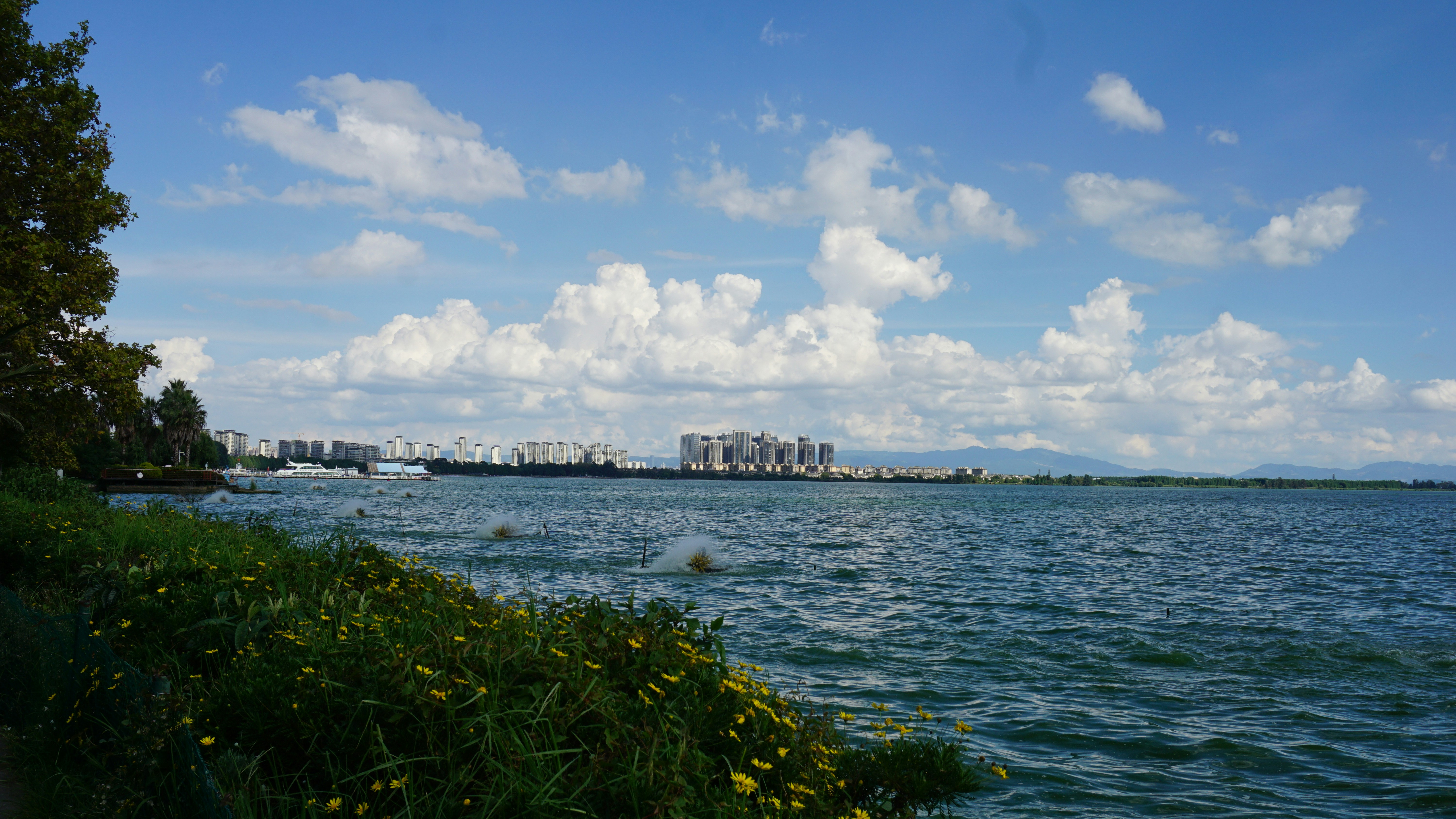 Buildings across a wide blue lake under clouds