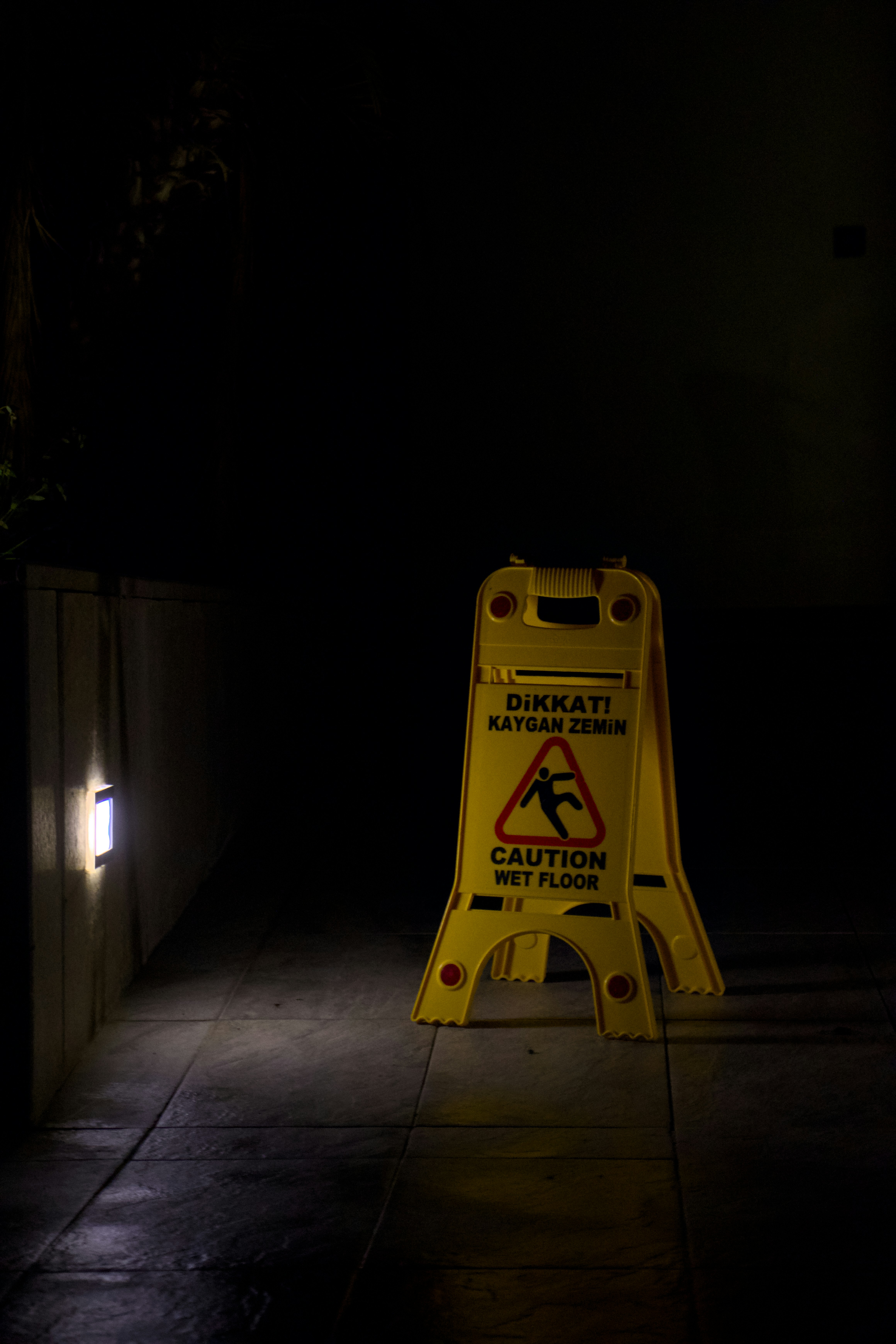 Low-Light Corridor: The Wet-Floor Warning Stands in Neon Yellow
