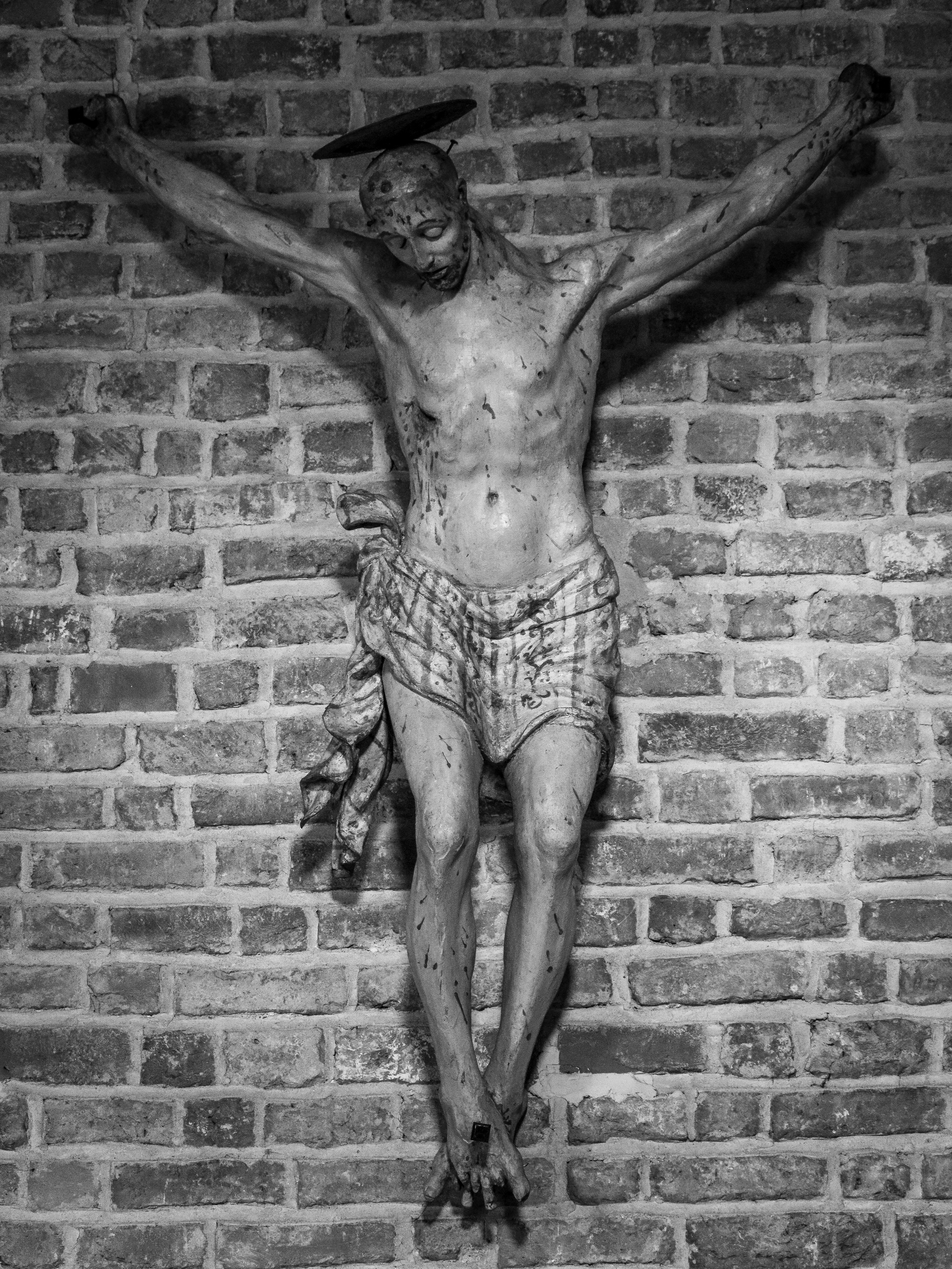 Crucifix on Brickwork: A Weathered Monochrome Sculpture