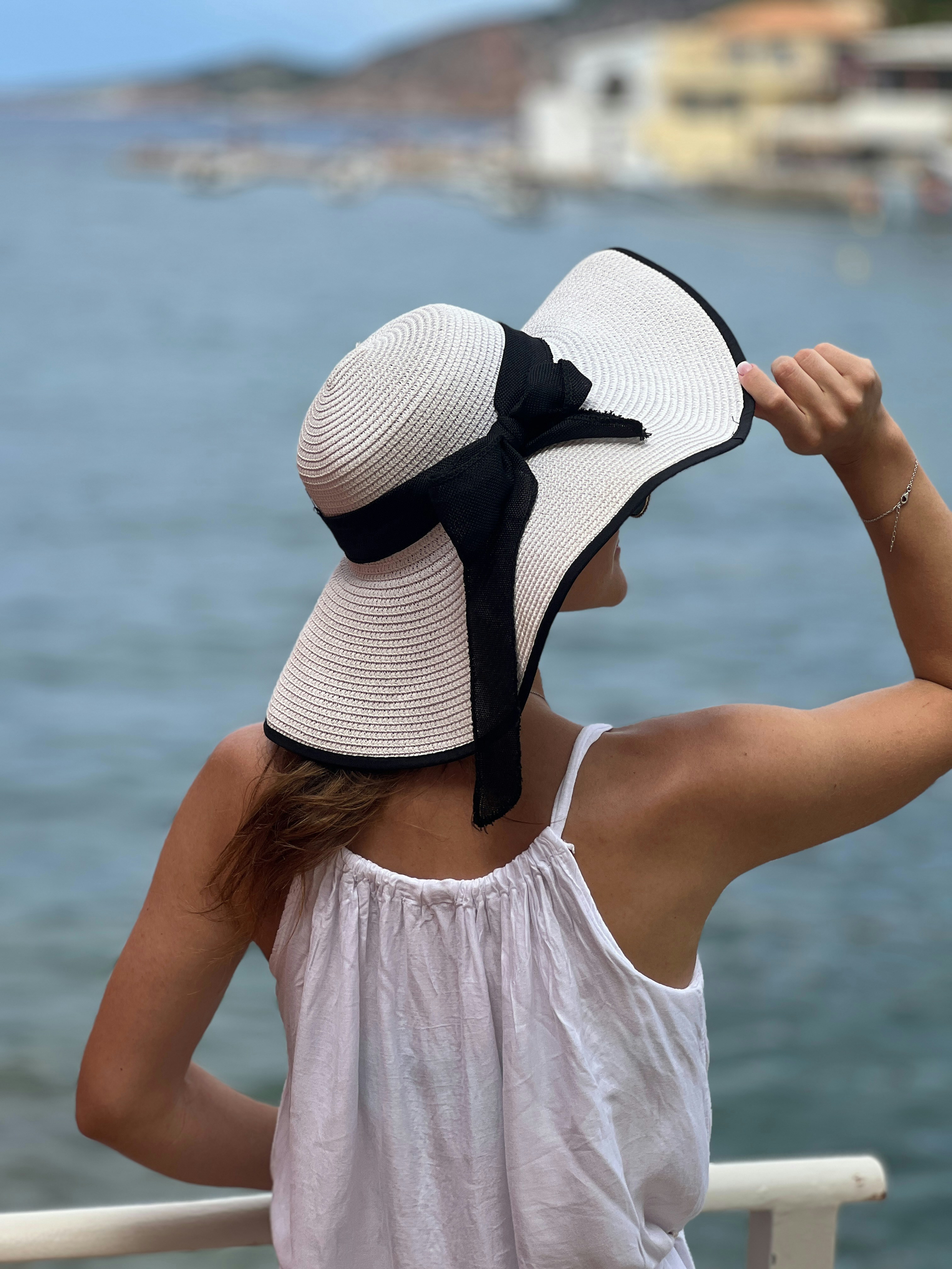 Woman wearing a white sun hat with black ribbon.