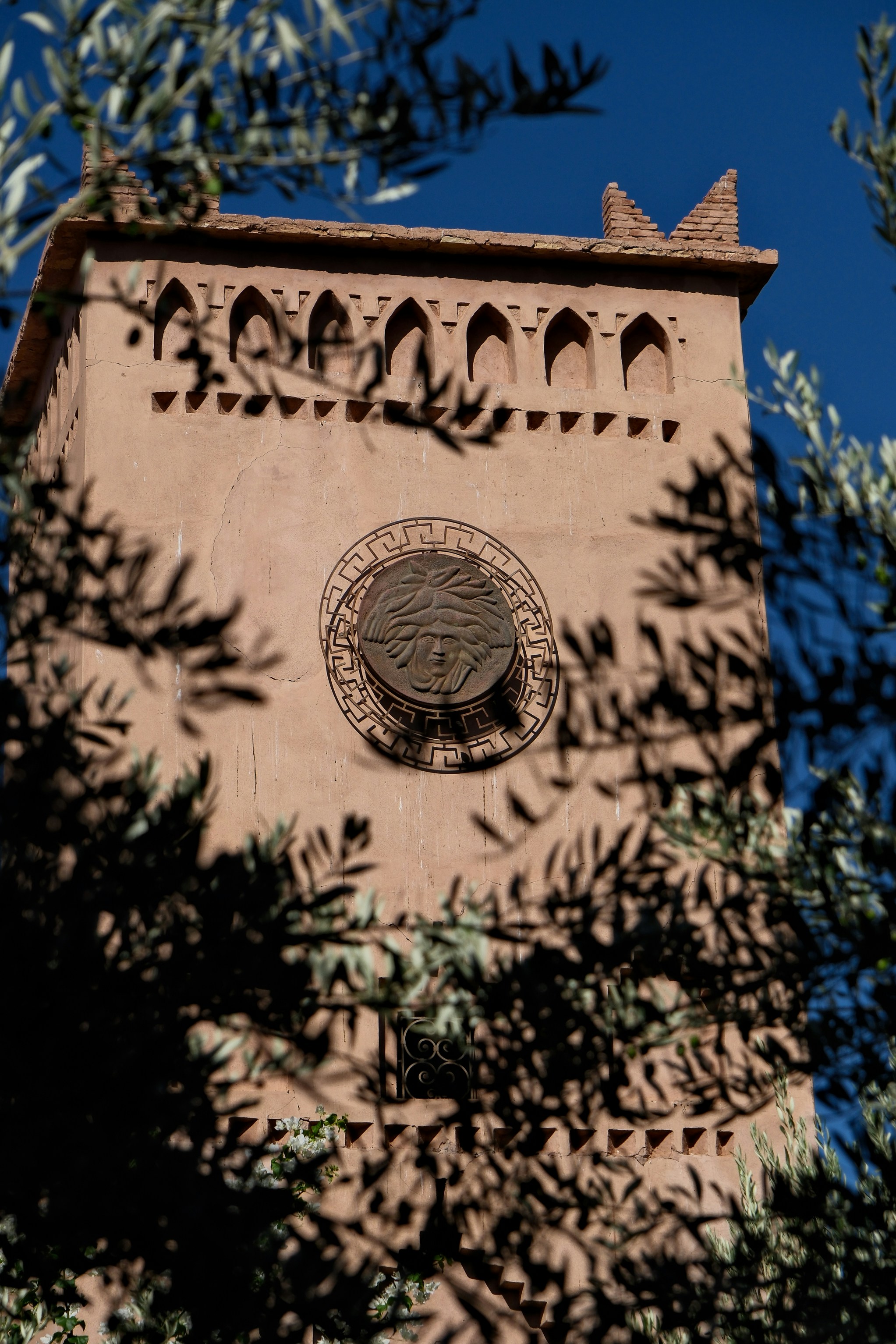 Medallion in the Sun: Sunlit Moorish Facade Framed by Shadowed Branches