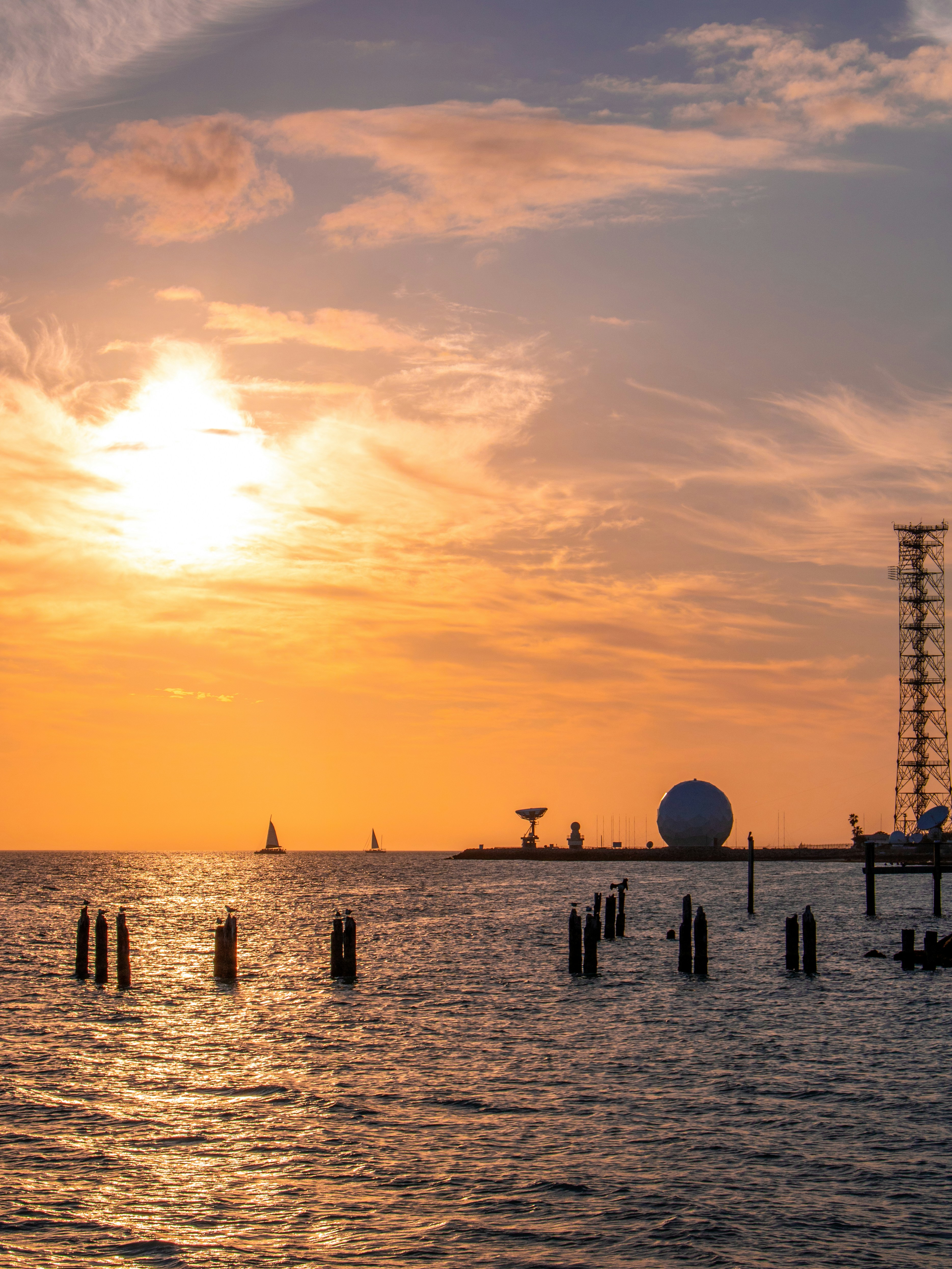 Dusk at the Harbor: Silhouettes, Pylons, and the Spherical Dome Against a Golden Sea